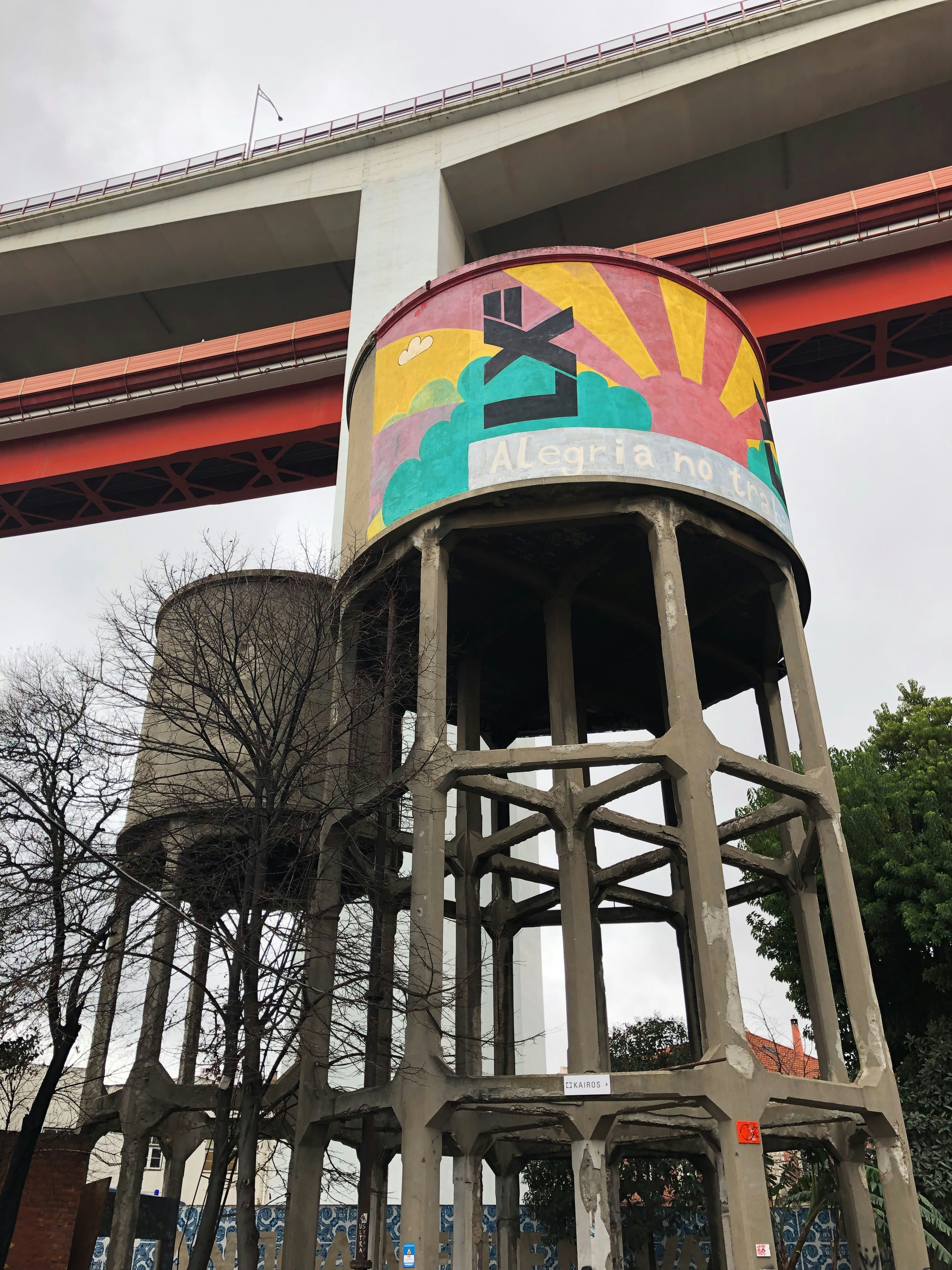 Water Tower under a Bridge: Colorful Tank Surrounded by Concrete Geometry