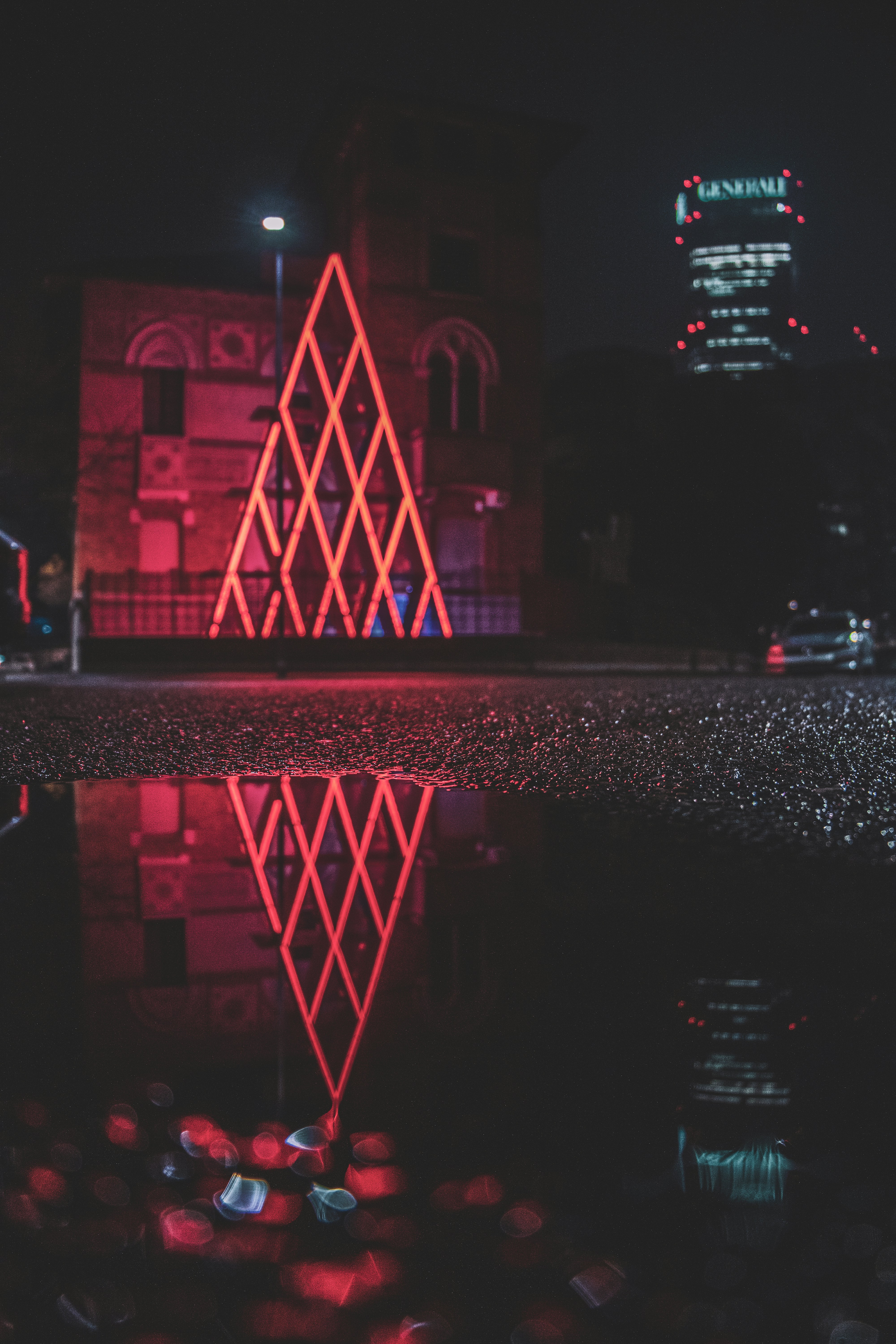 Neon Triangles on Wet Asphalt: A Nighttime Red Sculpture
