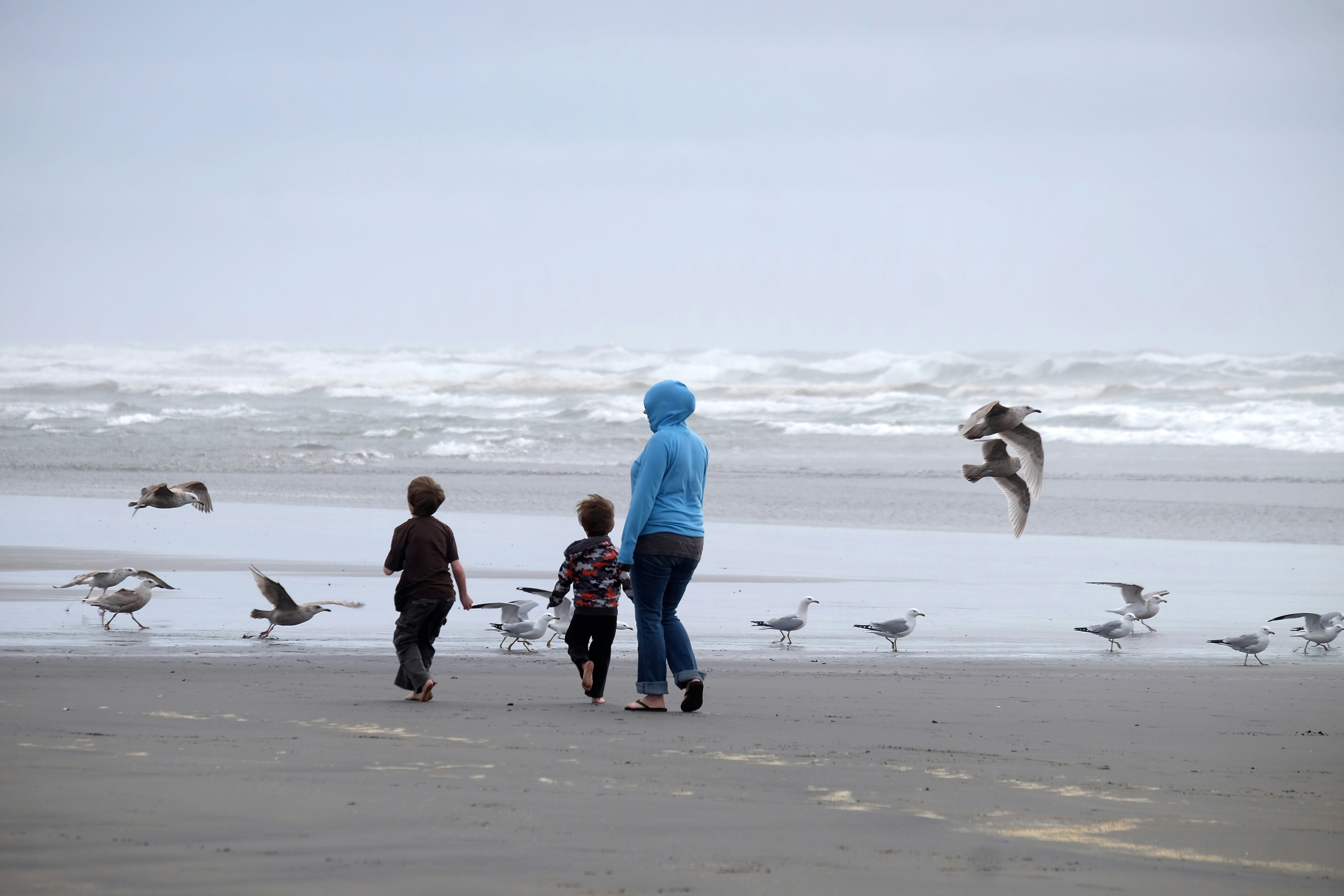 Blue‑hooded figure guiding two children along a seabed parade