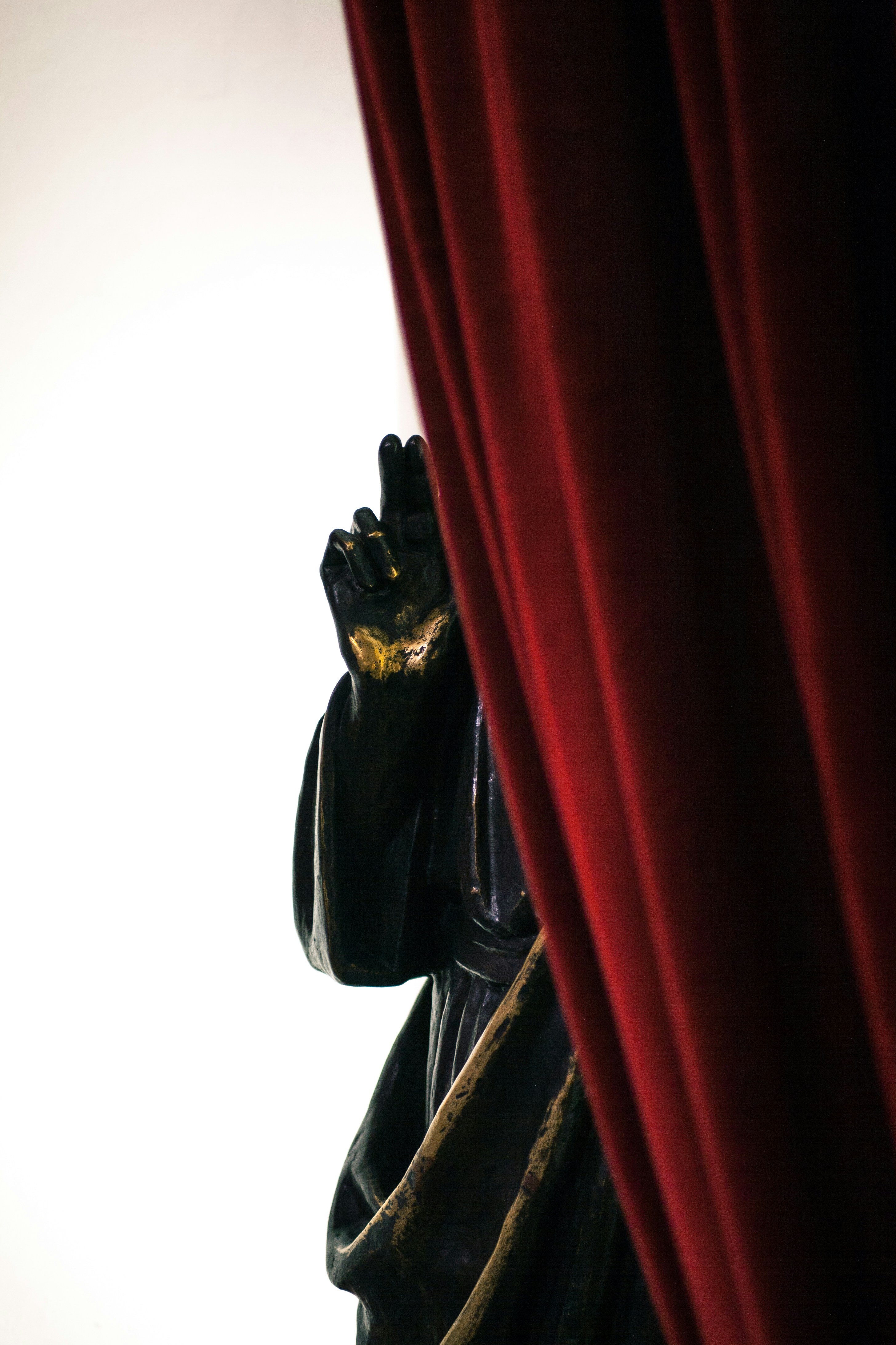 Veiled Gesture: A Statue Partially Revealed Behind Velvet Red