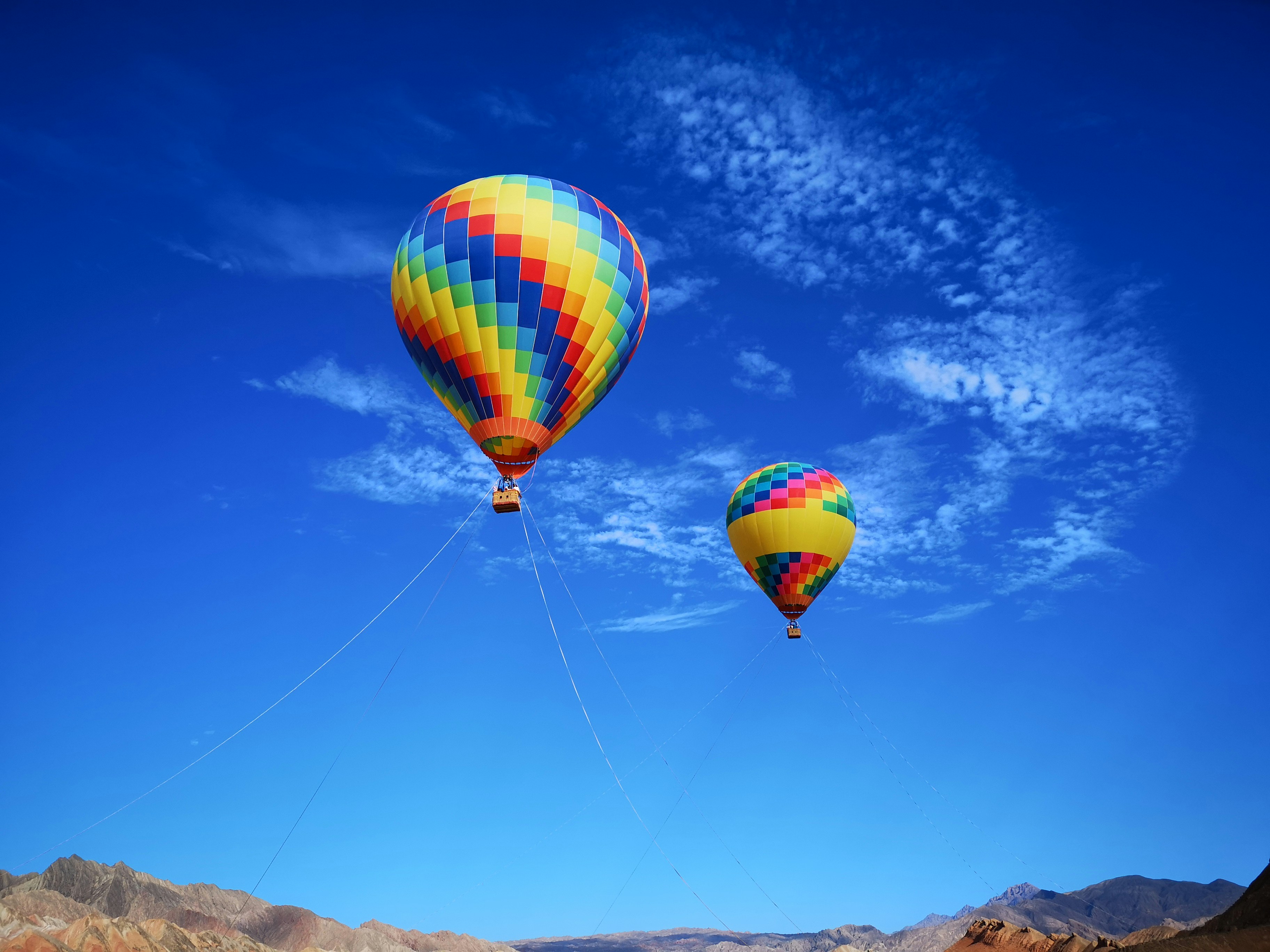Dos globos aerostáticos de colores variados bajo el cielo blanco y azul ...