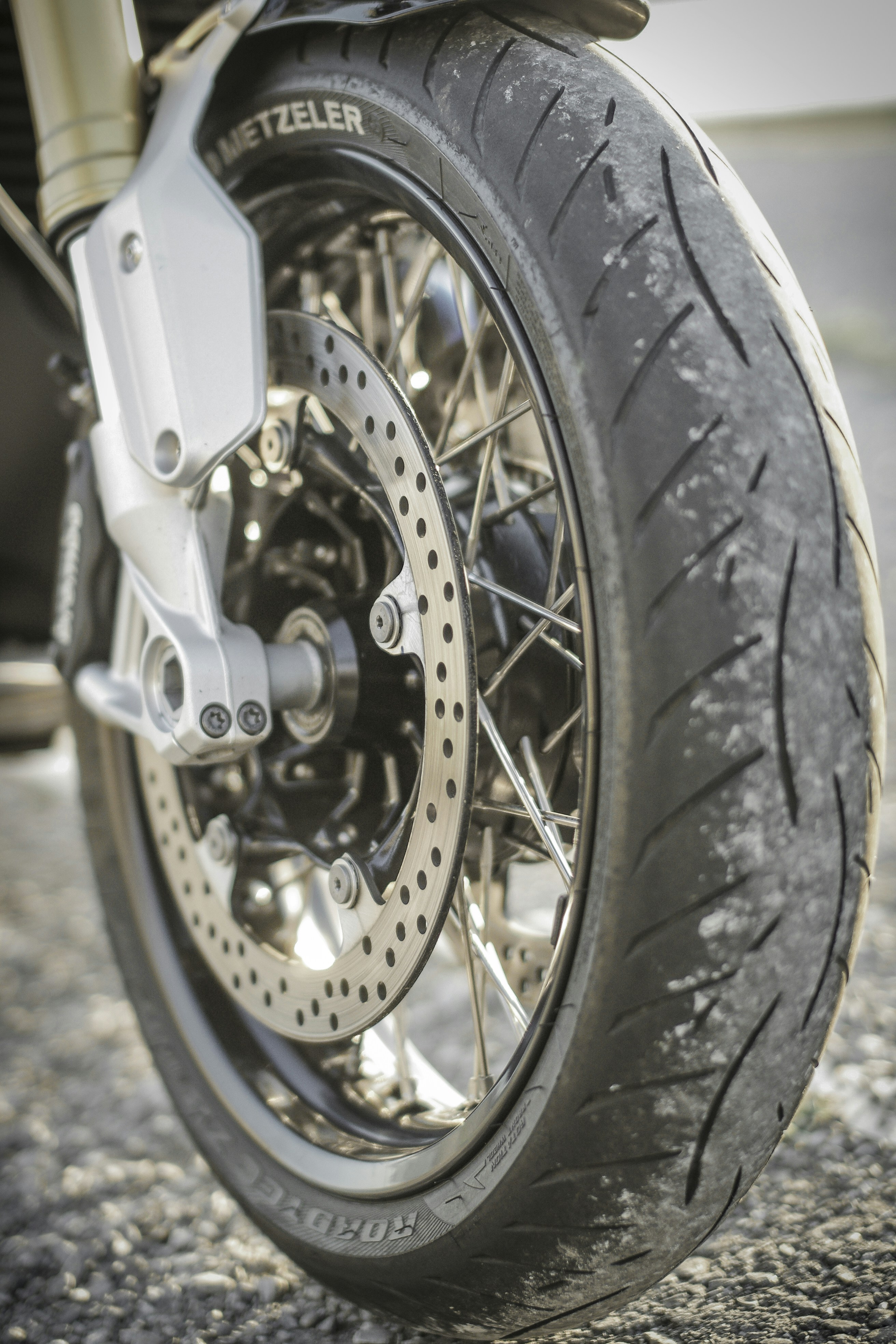 Close-up view of a motorcycle tire and brake assembly, showcasing intricate details of the wheel design and tread pattern.