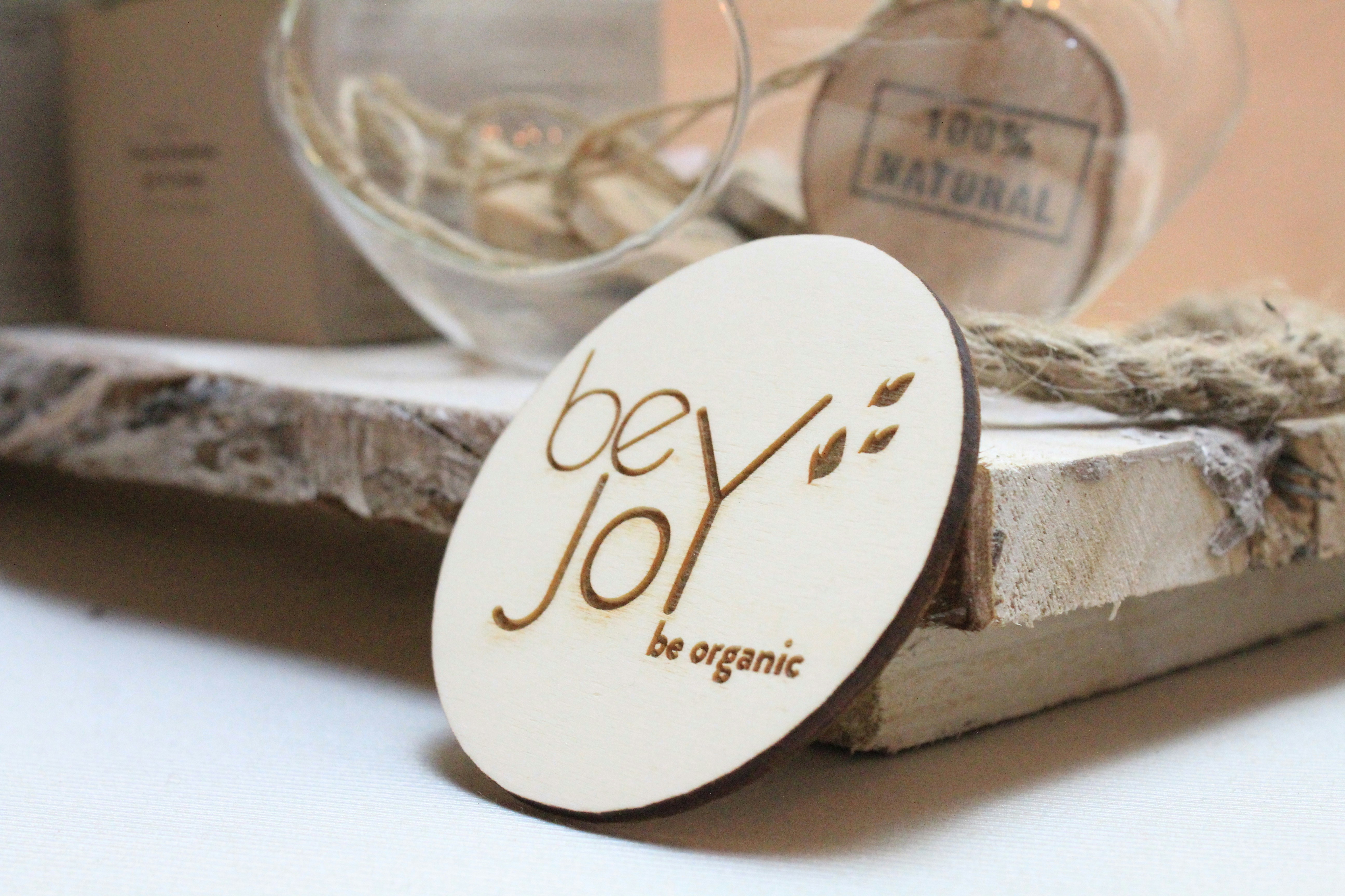 Be Joy Organic Round Tag resting on a rustic wooden plank