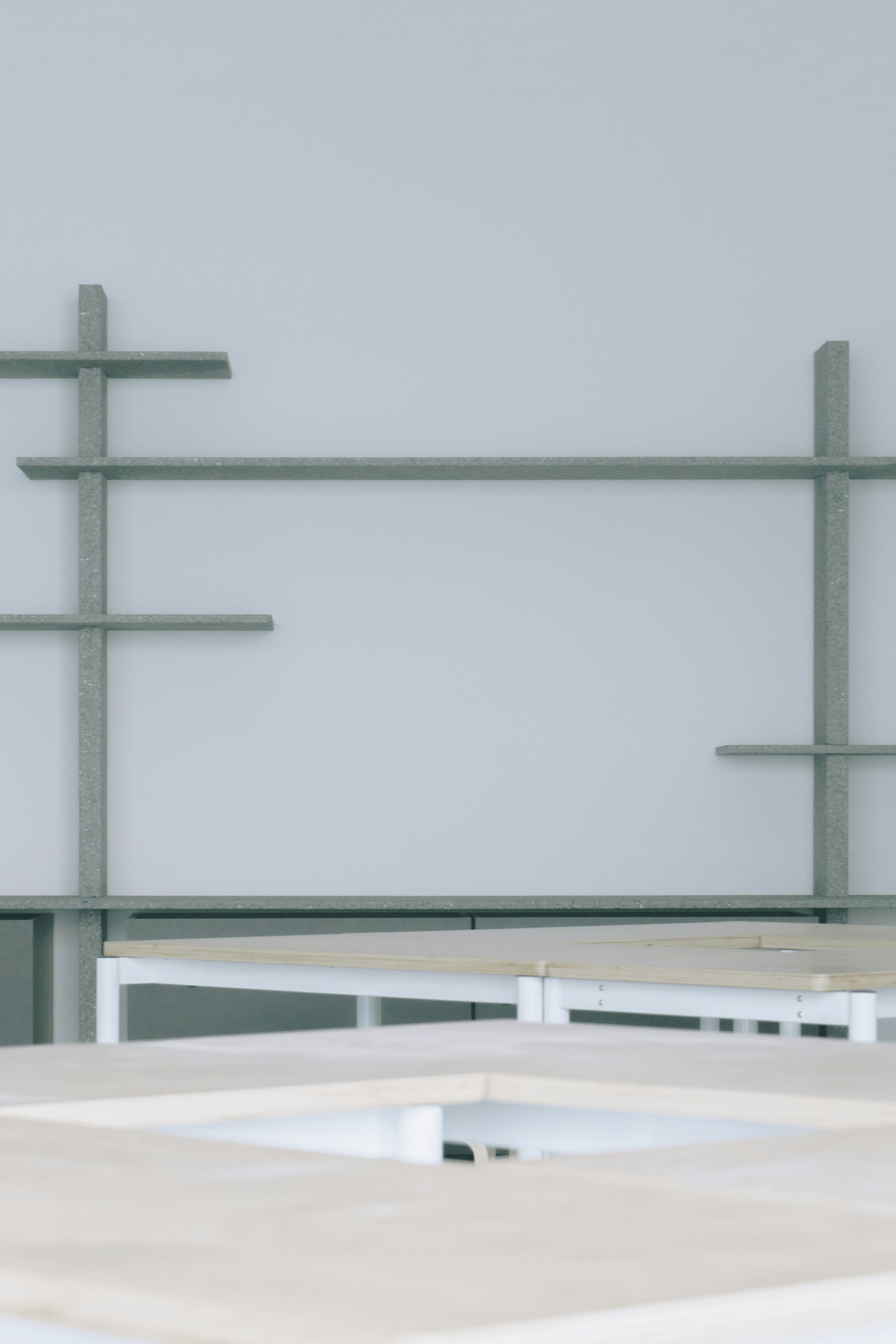 Abstract arrangement of minimalist furniture and shelving against a soft, neutral backdrop.