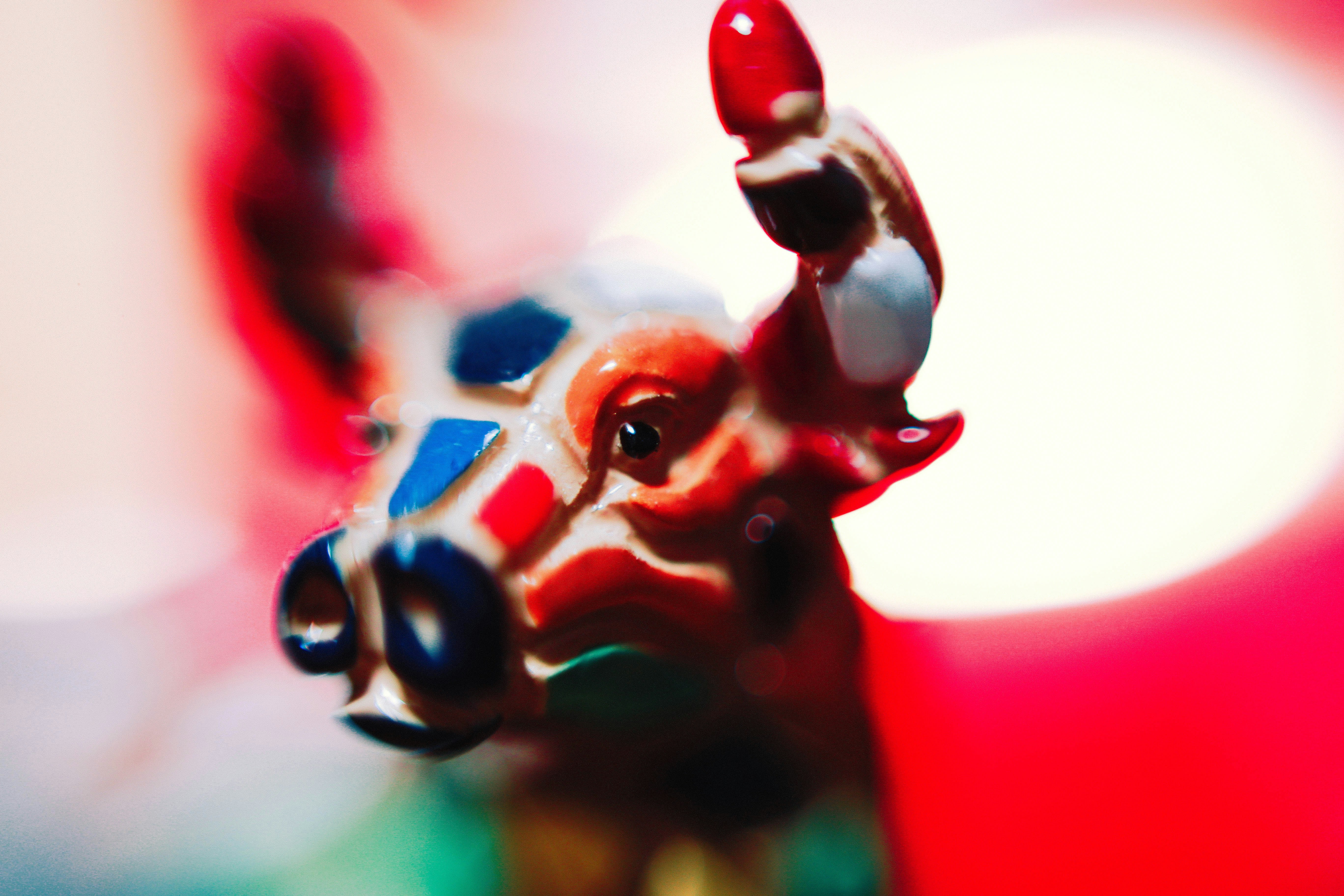 Colorful ceramic bull figurine with intricate details, set against a blurred, vibrant background.
