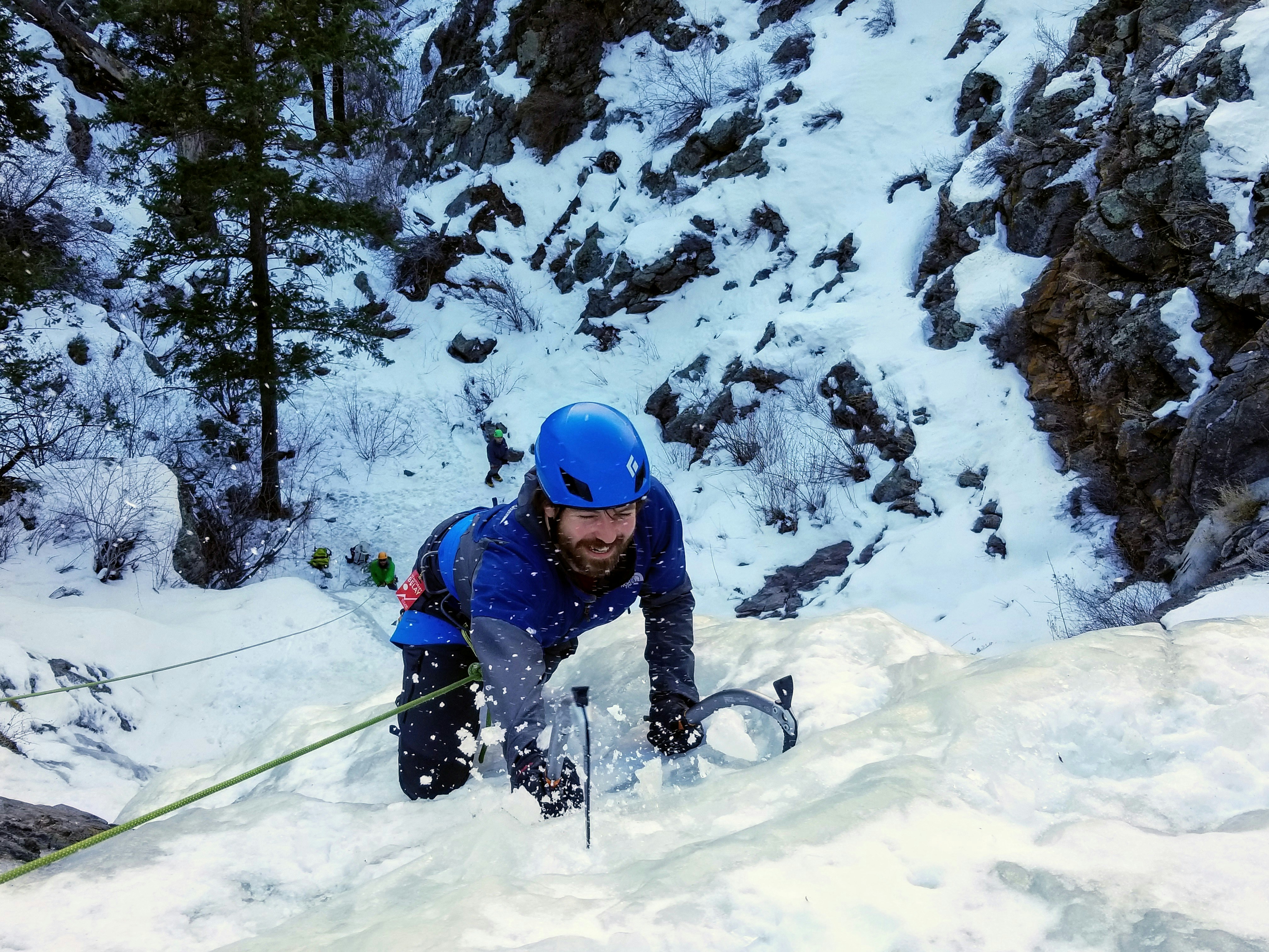 Blue Helmet Ascent on a Snow-Choked Rock Face