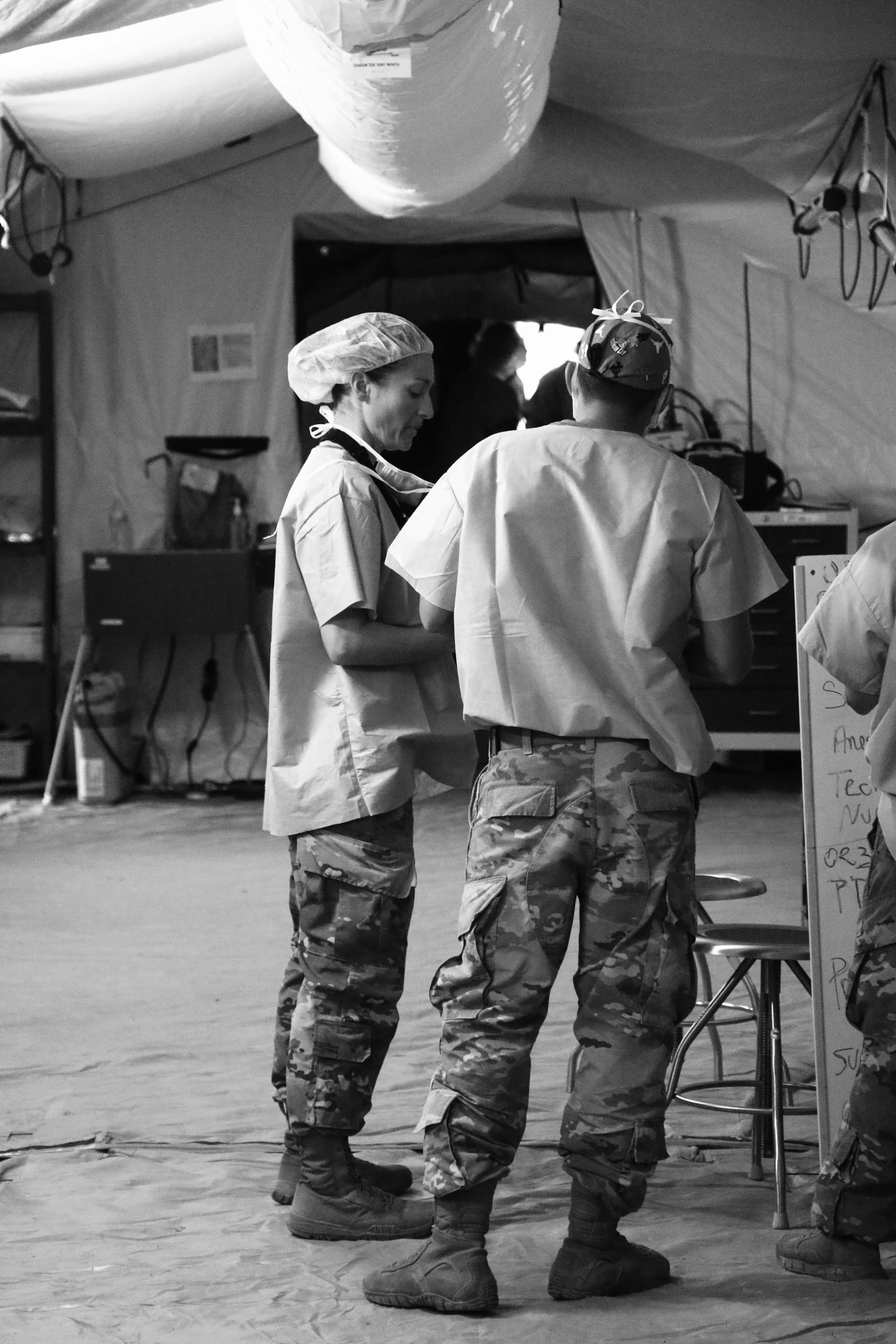 grayscale photo of two person standing near chairs
