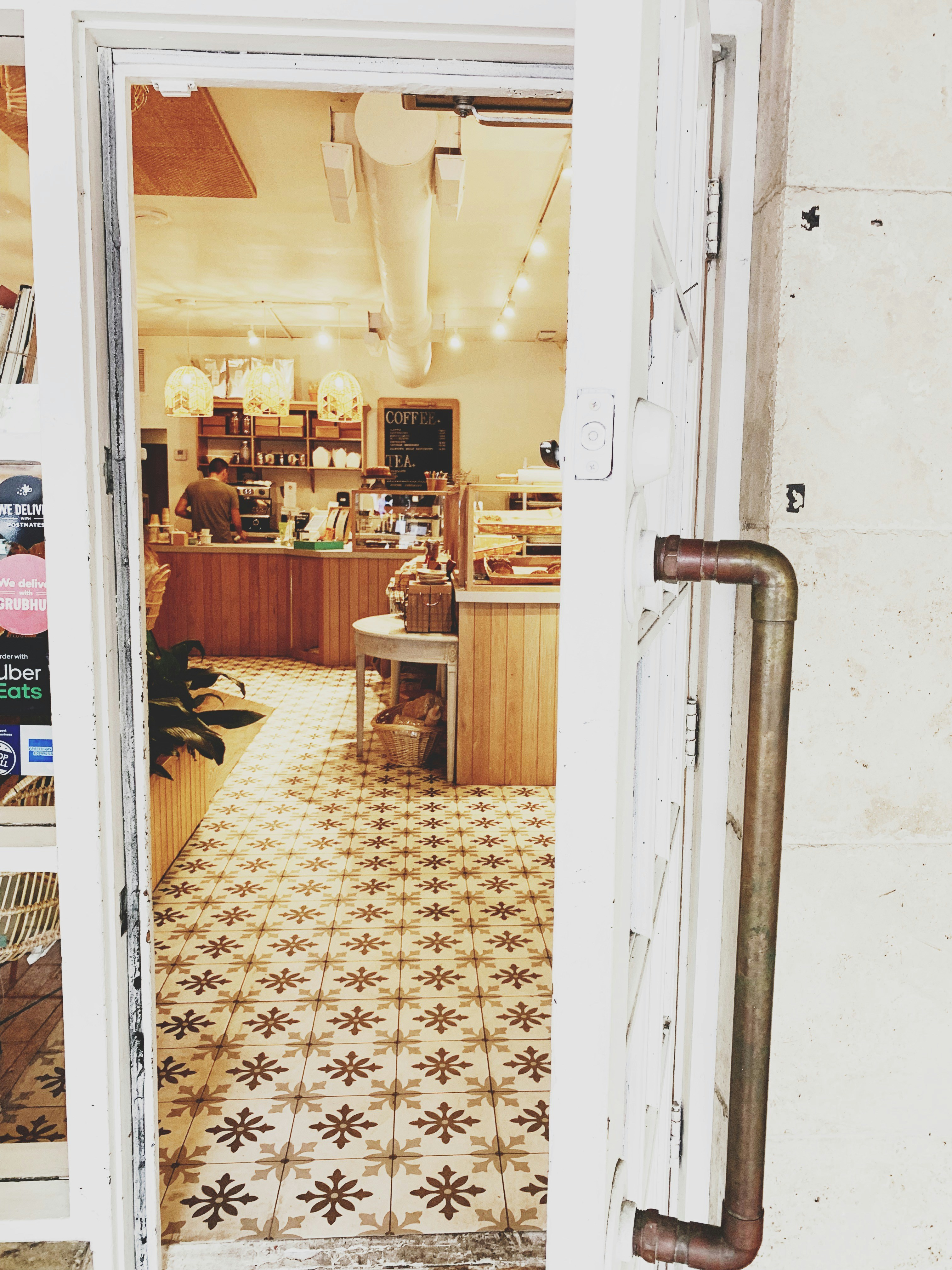 Warm Café Interior Framed by a Glass Door Over a Patterned Tile Floor