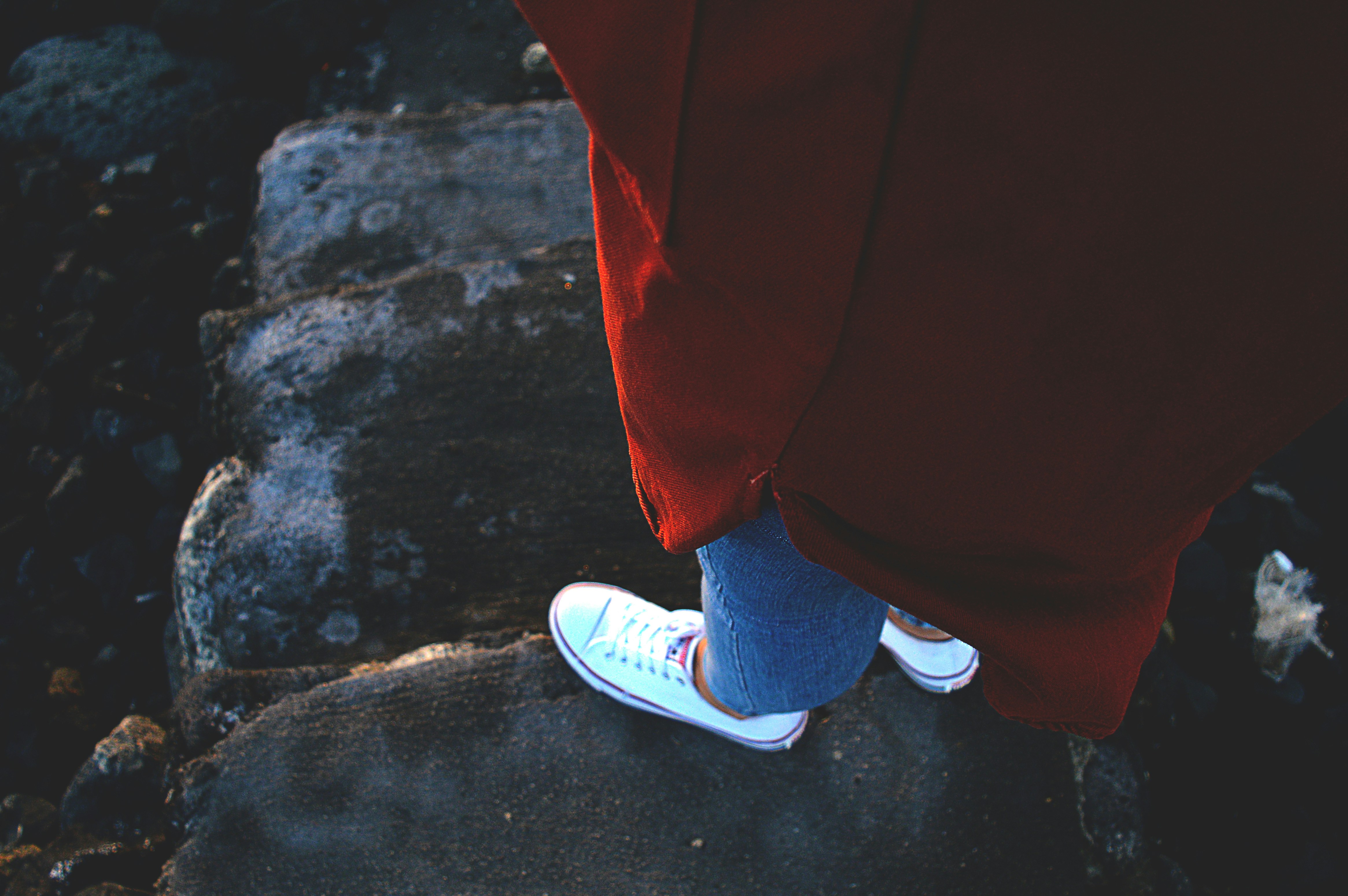 Red Garment, White Sneakers, and Weathered Rocks: A Quiet Shore Moment