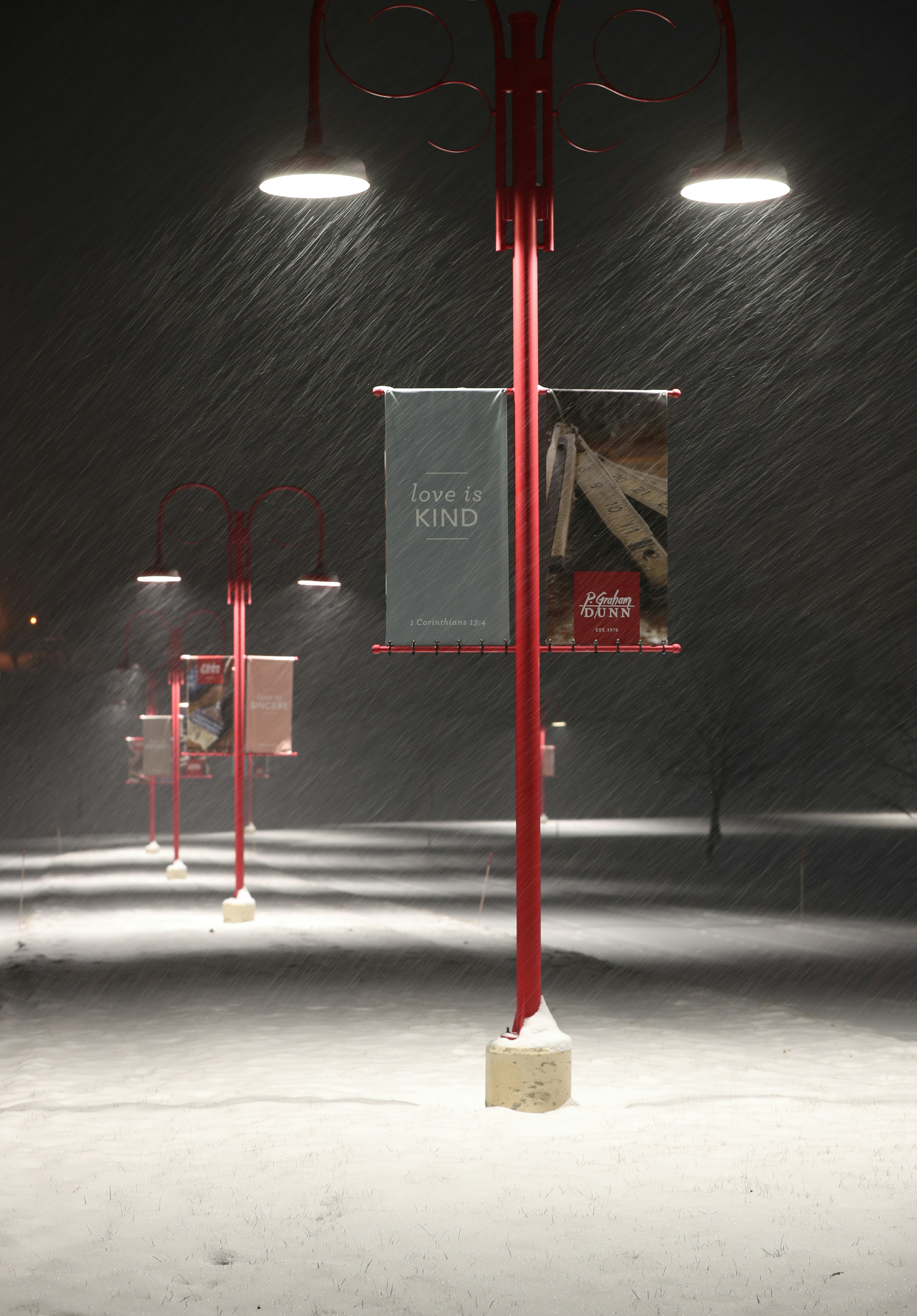 Snow-lit Promenade: Bannered Night Under Red Lampposts