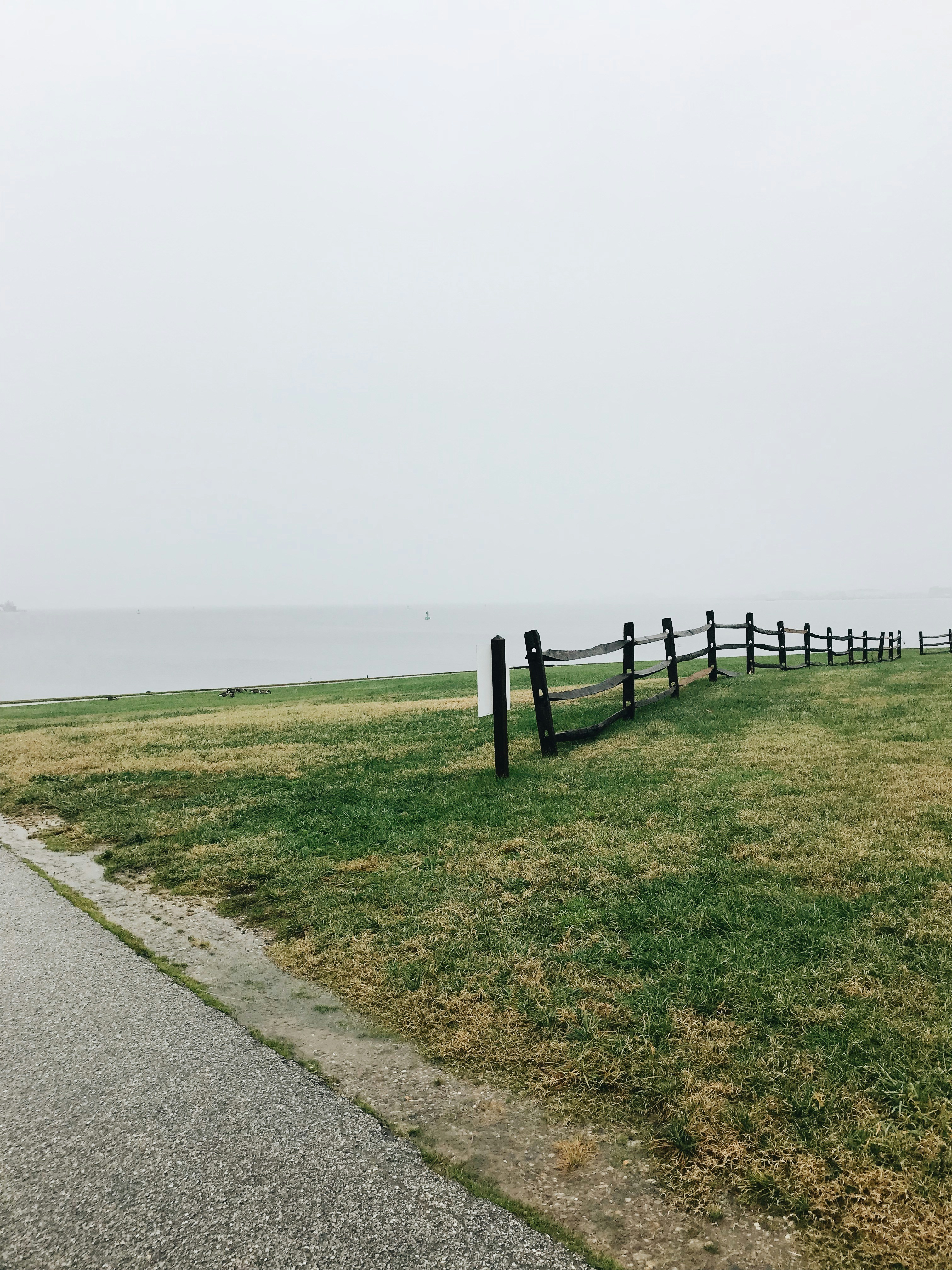 Fence Line Meets Quiet Lake Under Pale Skies