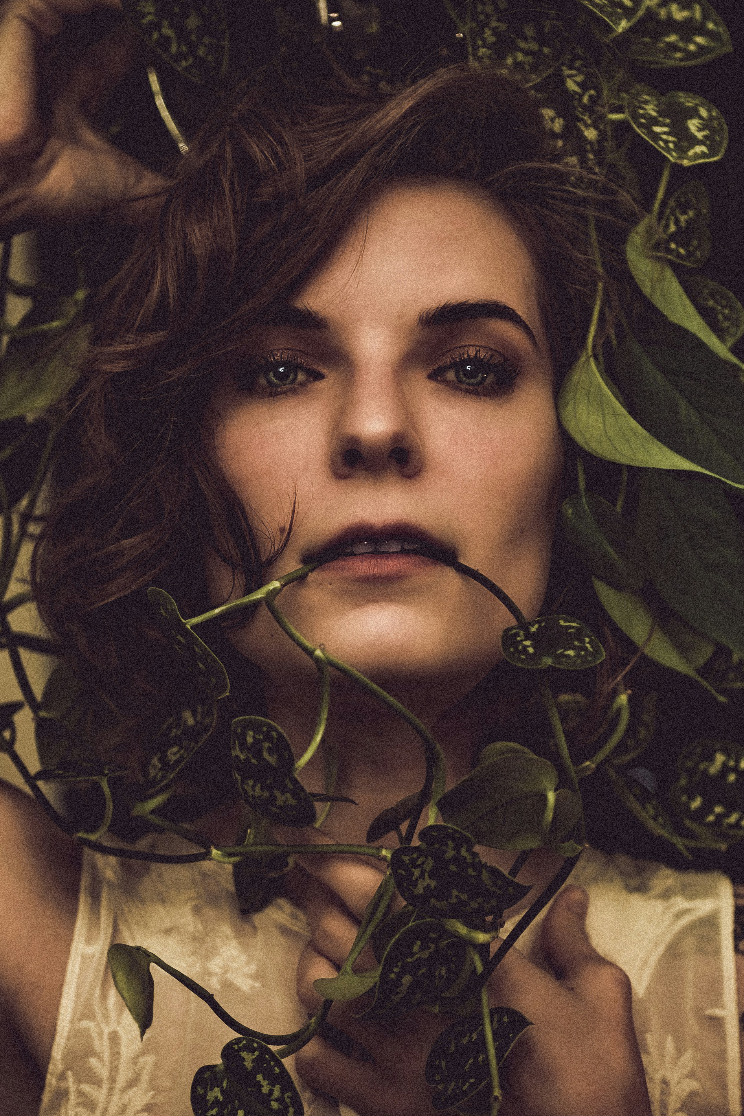 A woman surrounded by lush green vines, her expression reflecting a deep connection with nature. The intricate interplay of foliage and emotion creates a captivating visual narrative.