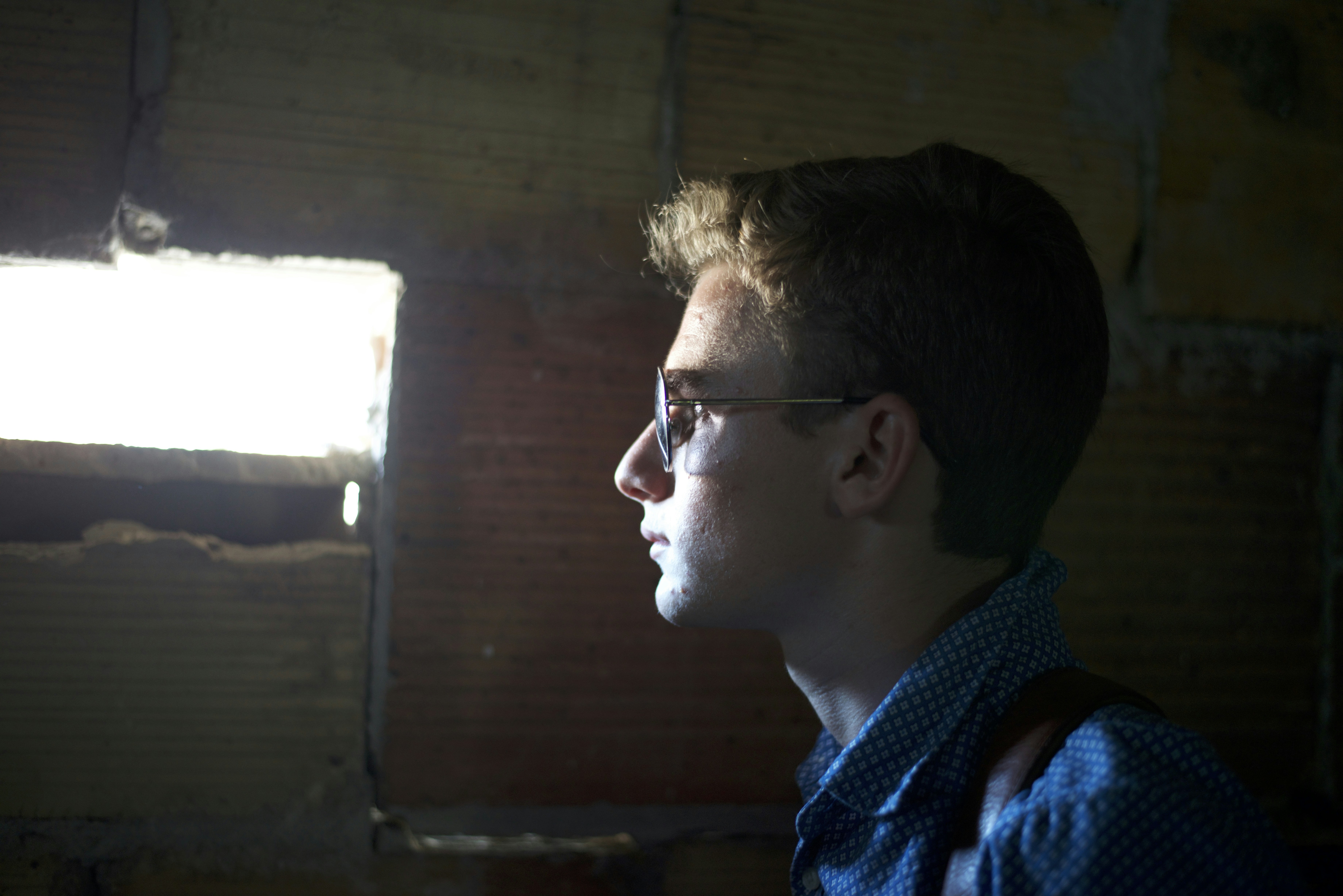 Backlit Profile Against Brick: A Quiet Portrait with Window Light