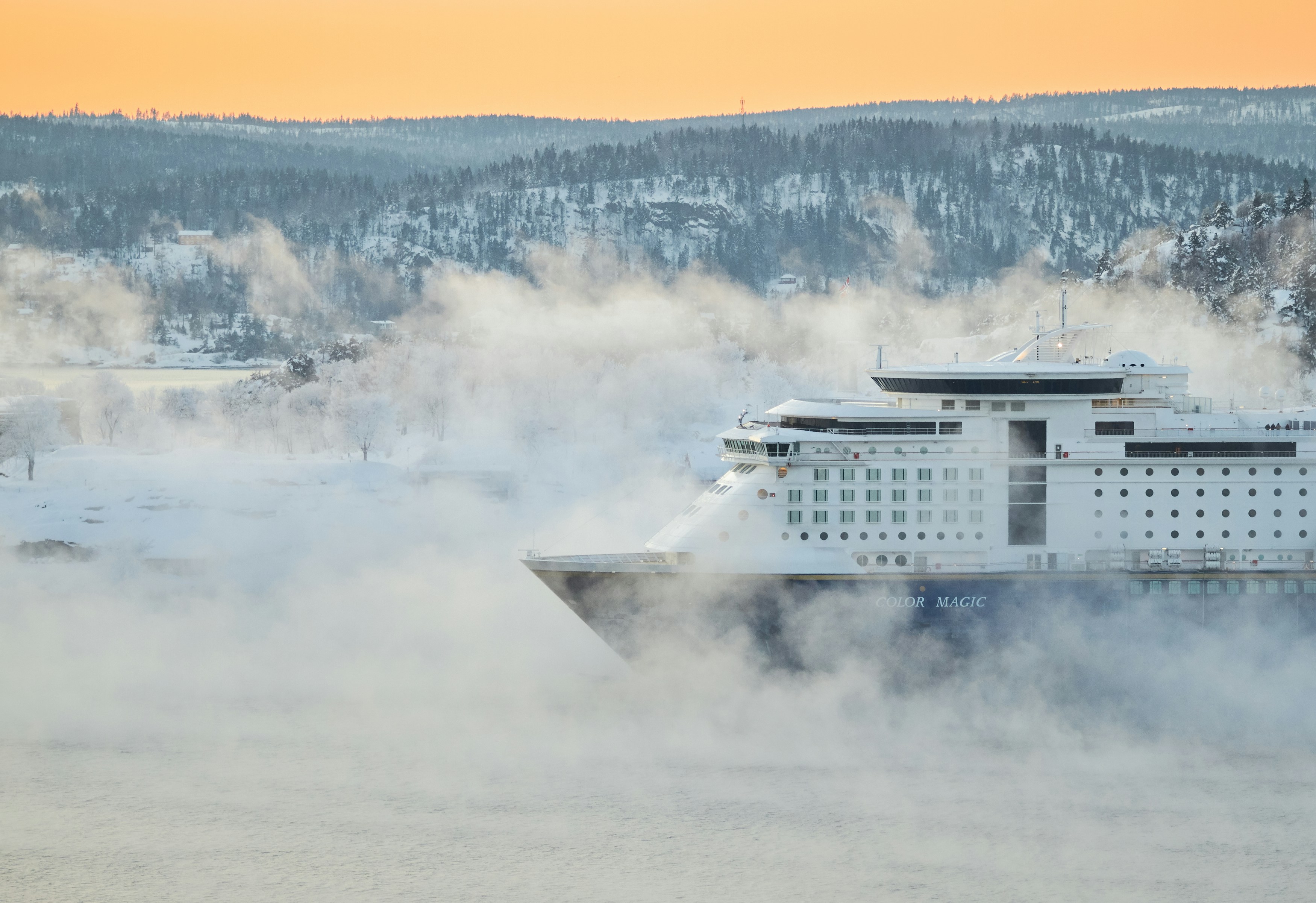 A majestic cruise ship emerges from a blanket of fog on a snowy landscape, illuminated by the soft hues of dawn.