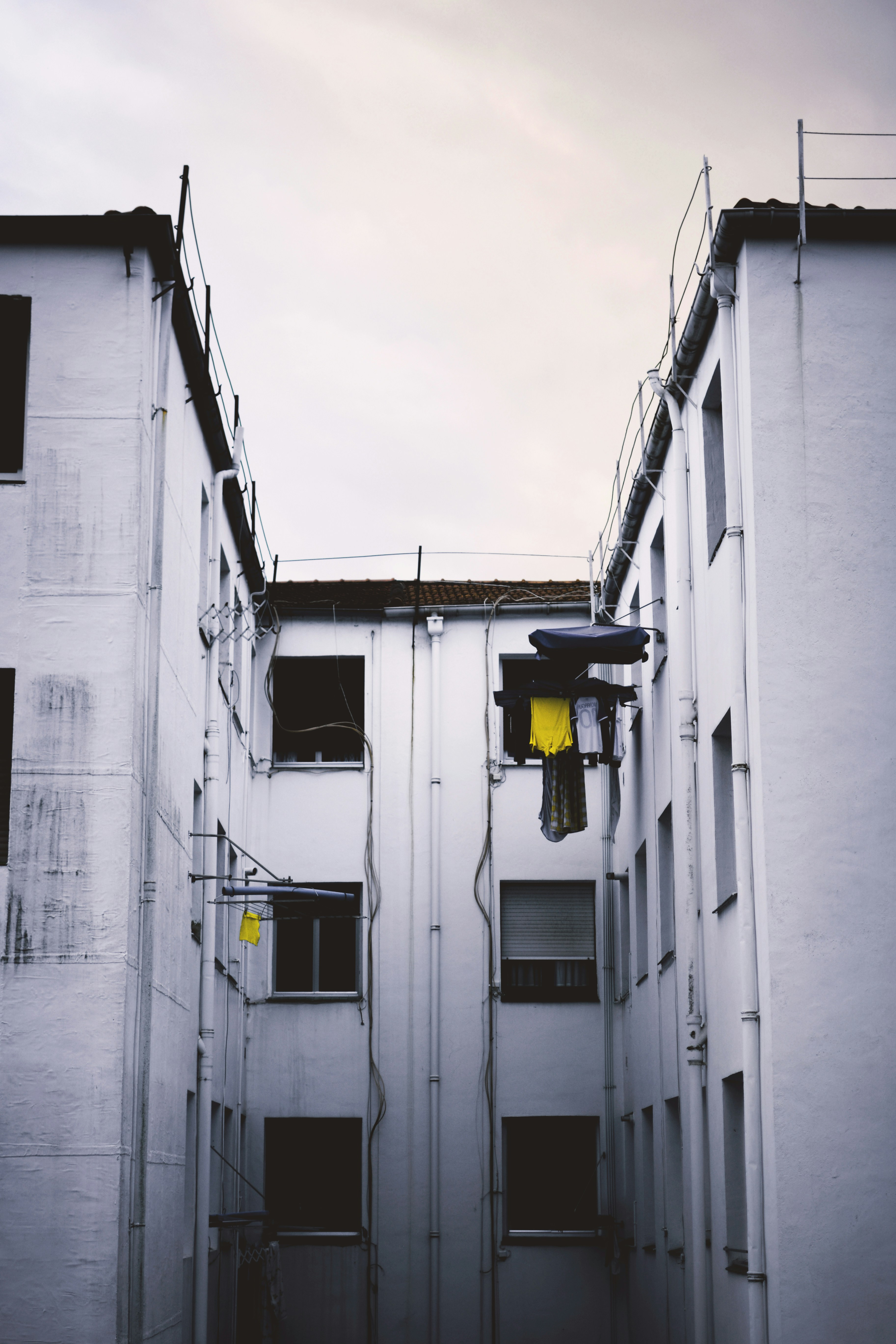 Clothes hanging between two stark white buildings under a moody sky, creating a contrast of color and texture.
