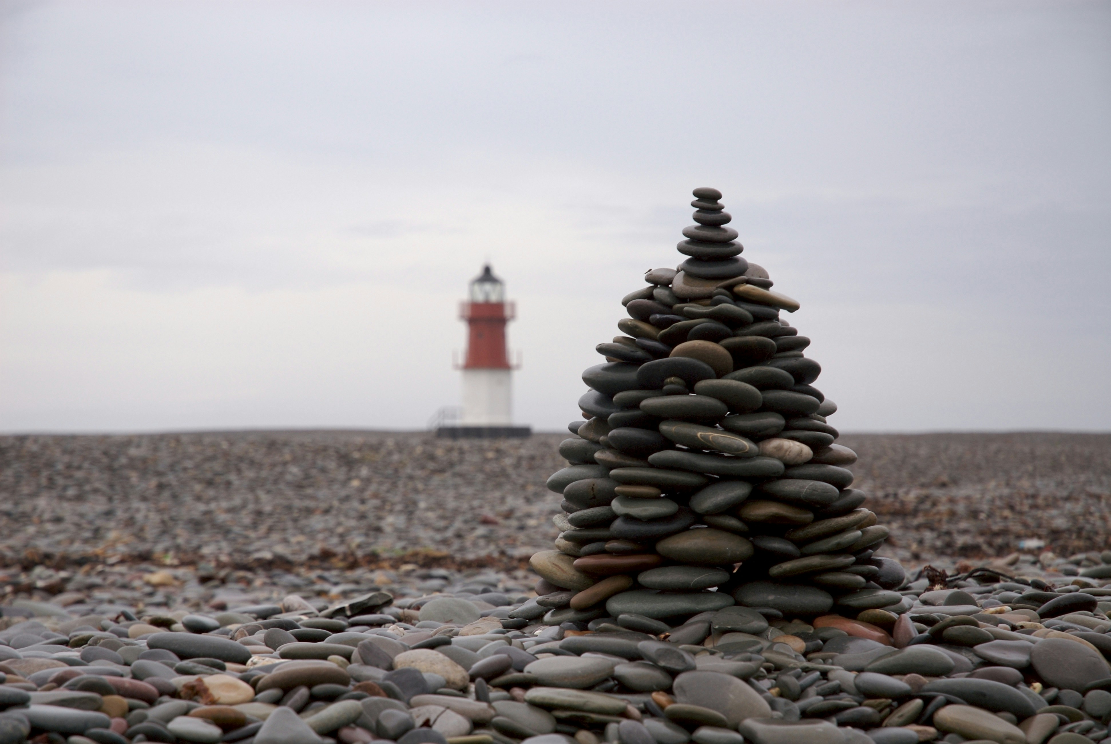Selective focus photography of stocked stones with lighthouse ...