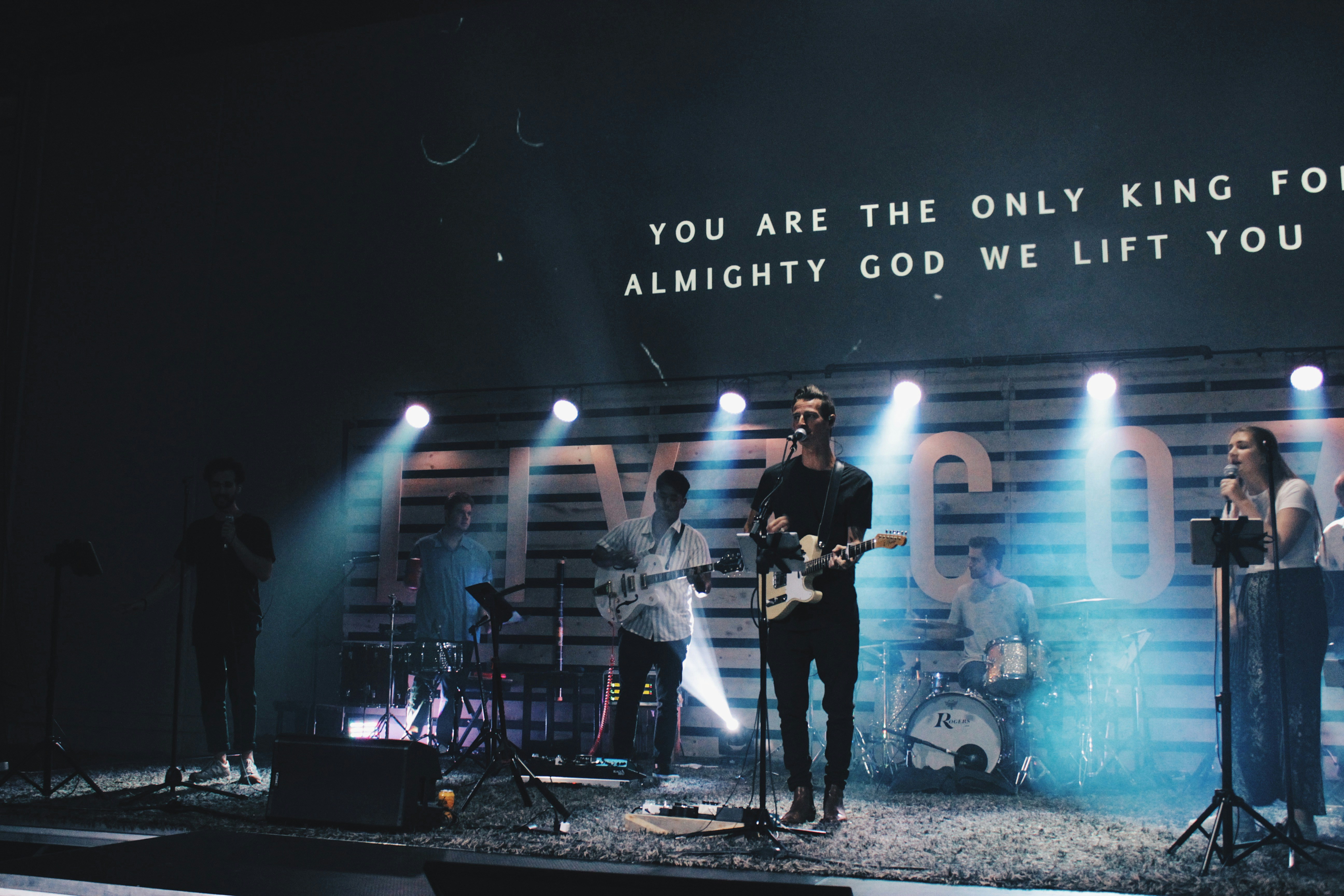 Band performing on stage with vibrant lighting and projected lyrics.