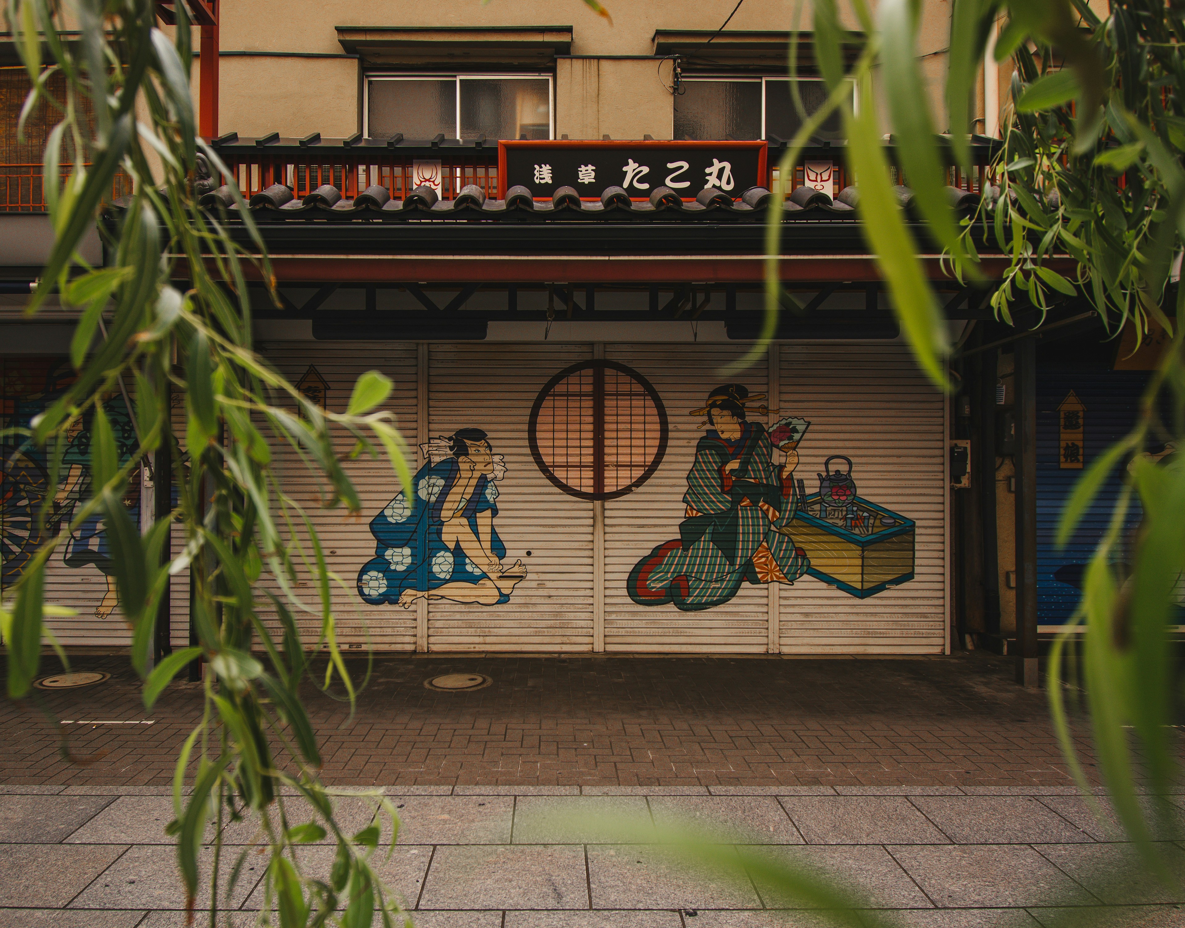 Shuttered Shrine: A Mural of Traditional Figures on a Closed Shopfront