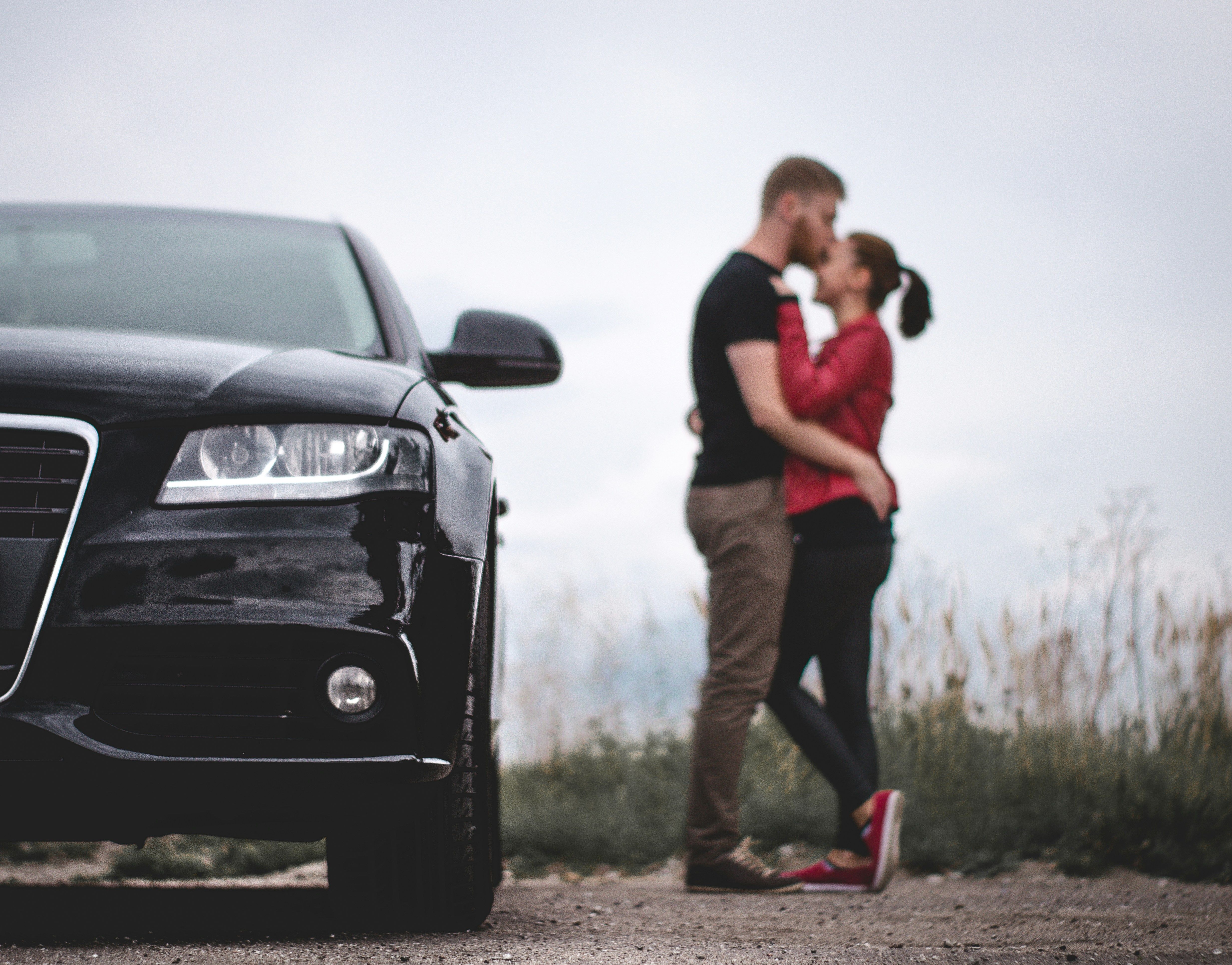 Between Grasses and Chrome: A Quiet Kiss at the Car's Edge