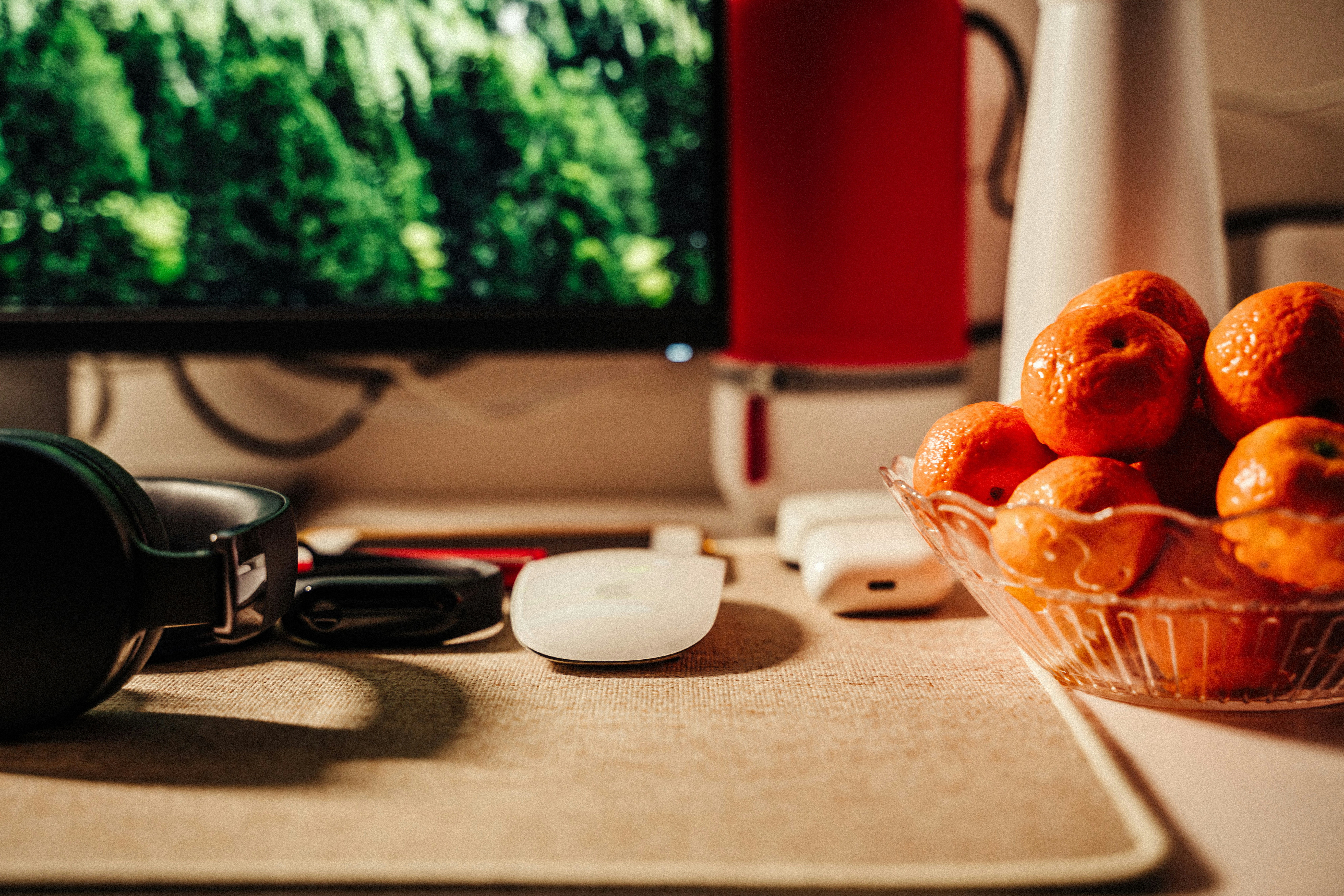 Quiet Focus at Desk Level: A White Charging Case Anchored by a Bowl of Oranges