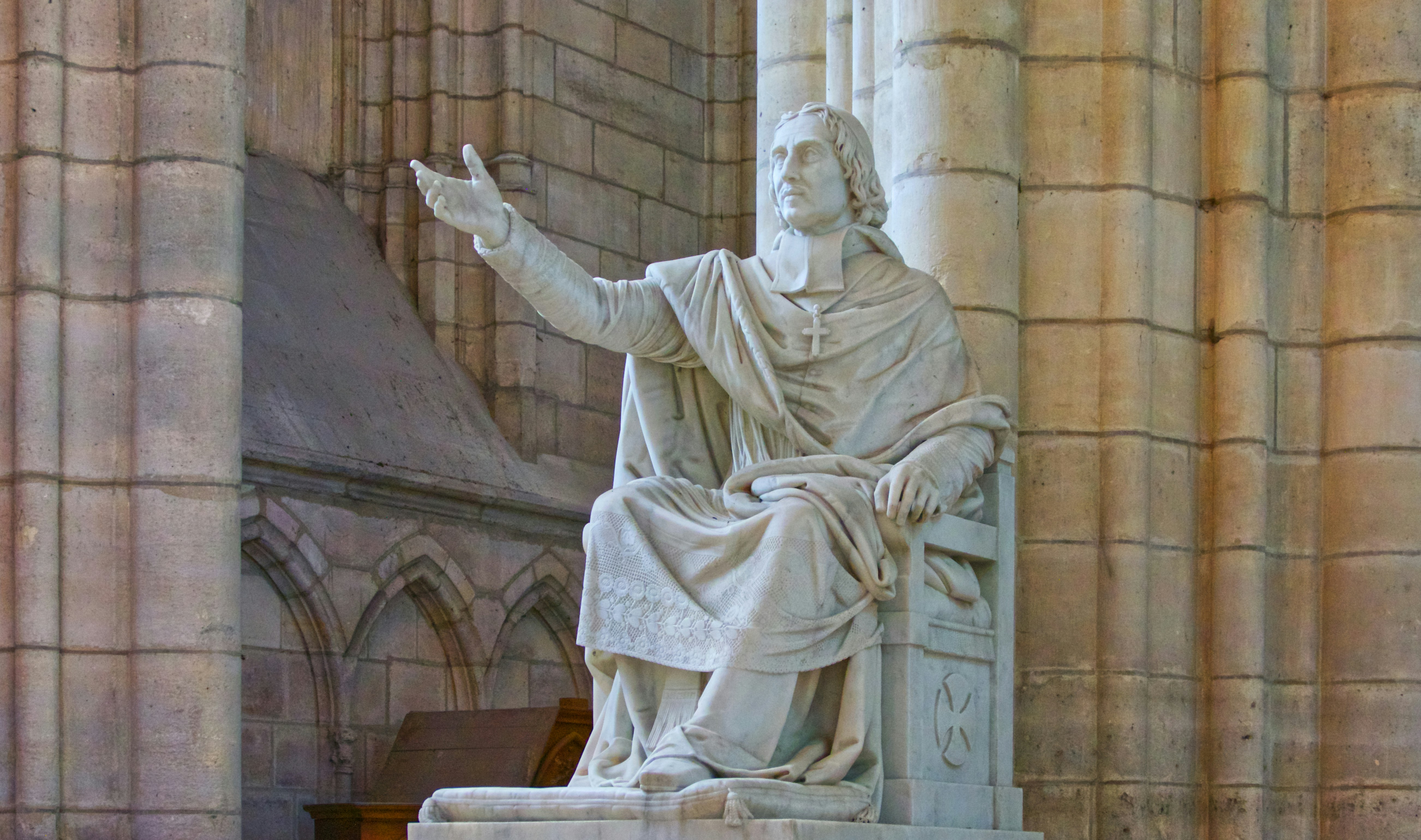 Marble statue of a seated figure gesturing dramatically inside a grand cathedral with towering arches.