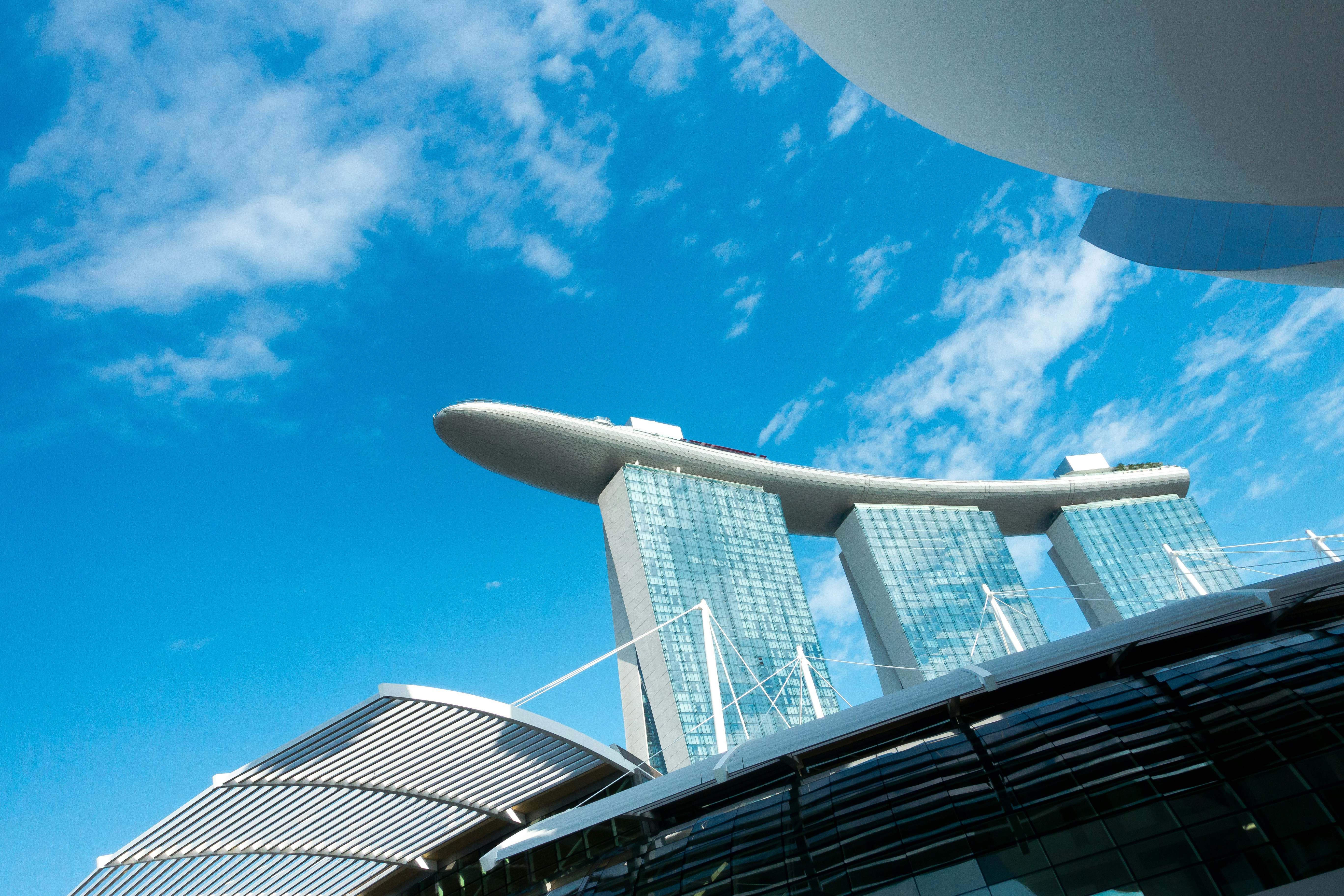 Marina Bay Sands hotel towers against a vibrant blue sky with scattered clouds.