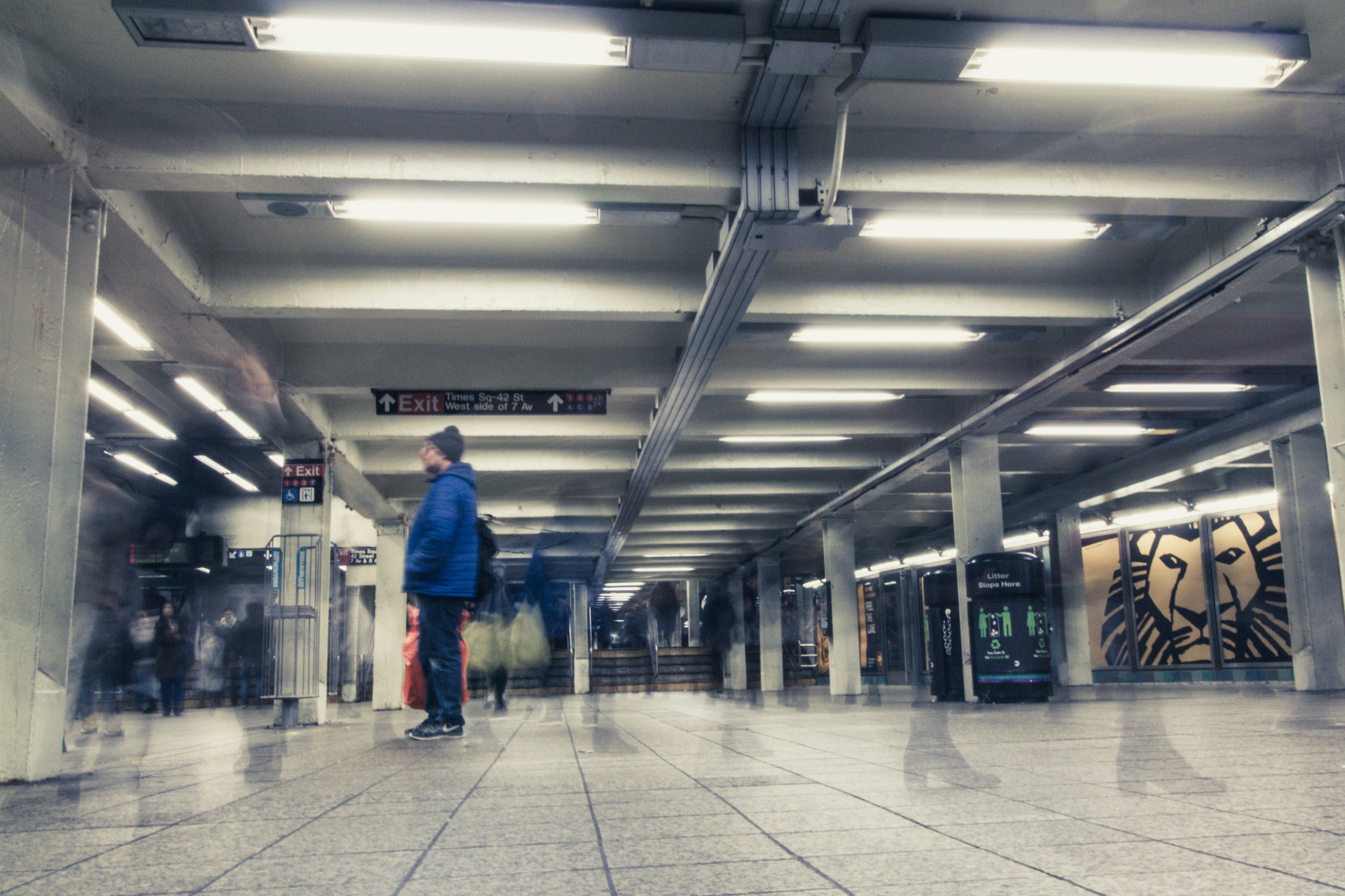 Blue-Jacket Standstill Amidst Blur in a Subterranean Hall