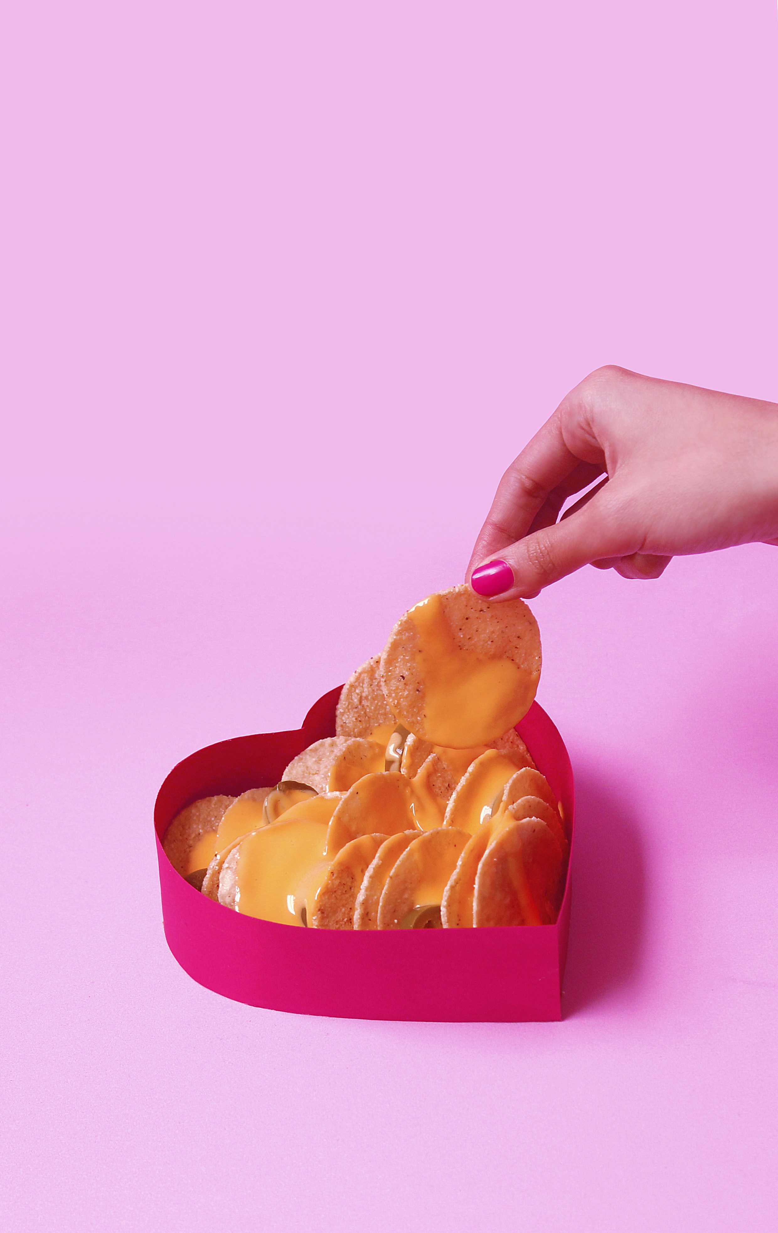 Cheese-Drizzled Chips in a Heart-Shaped Tray Against Blush Pink