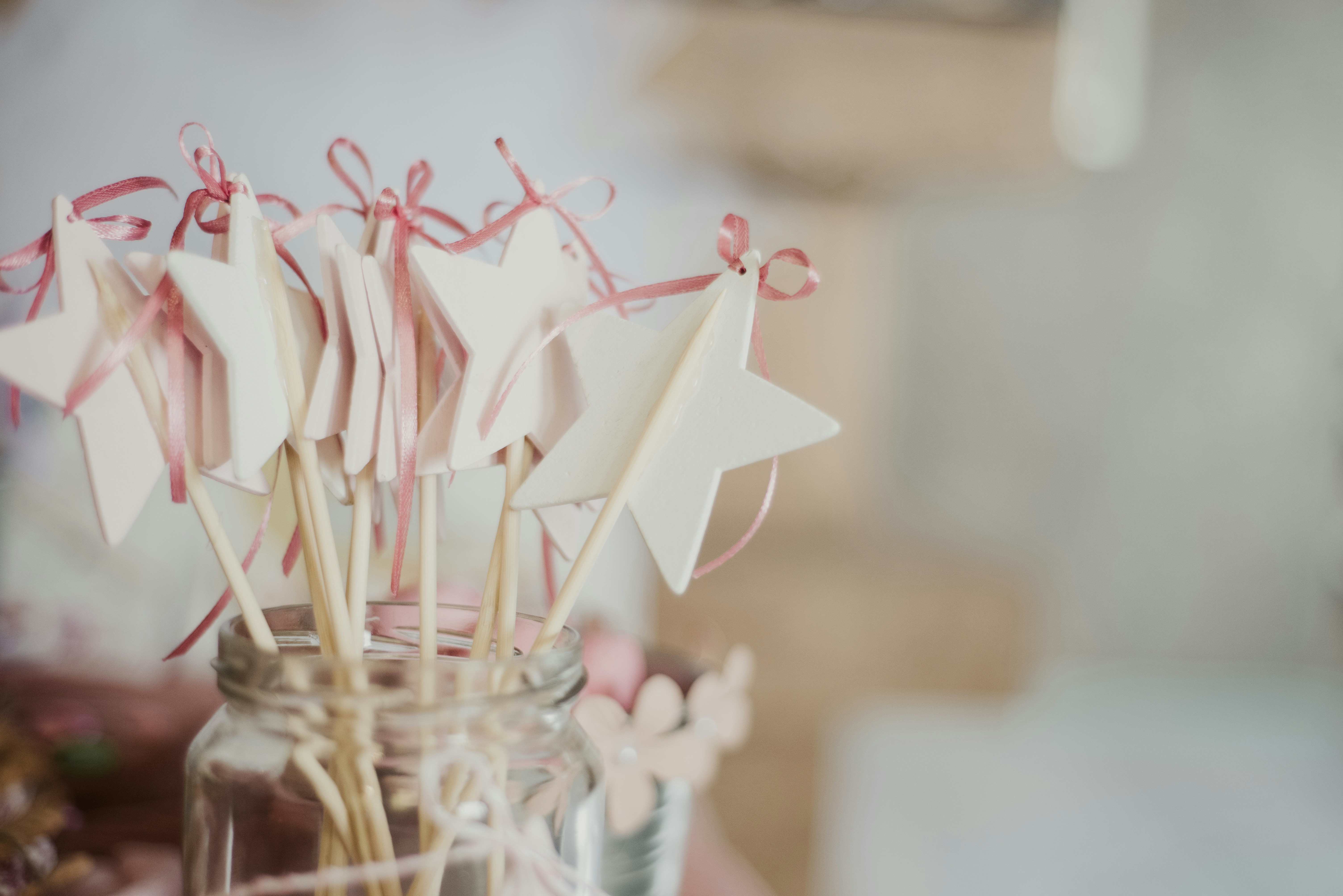 Delicate pink and white star-shaped treats on sticks displayed in a glass jar, perfect for a festive occasion.