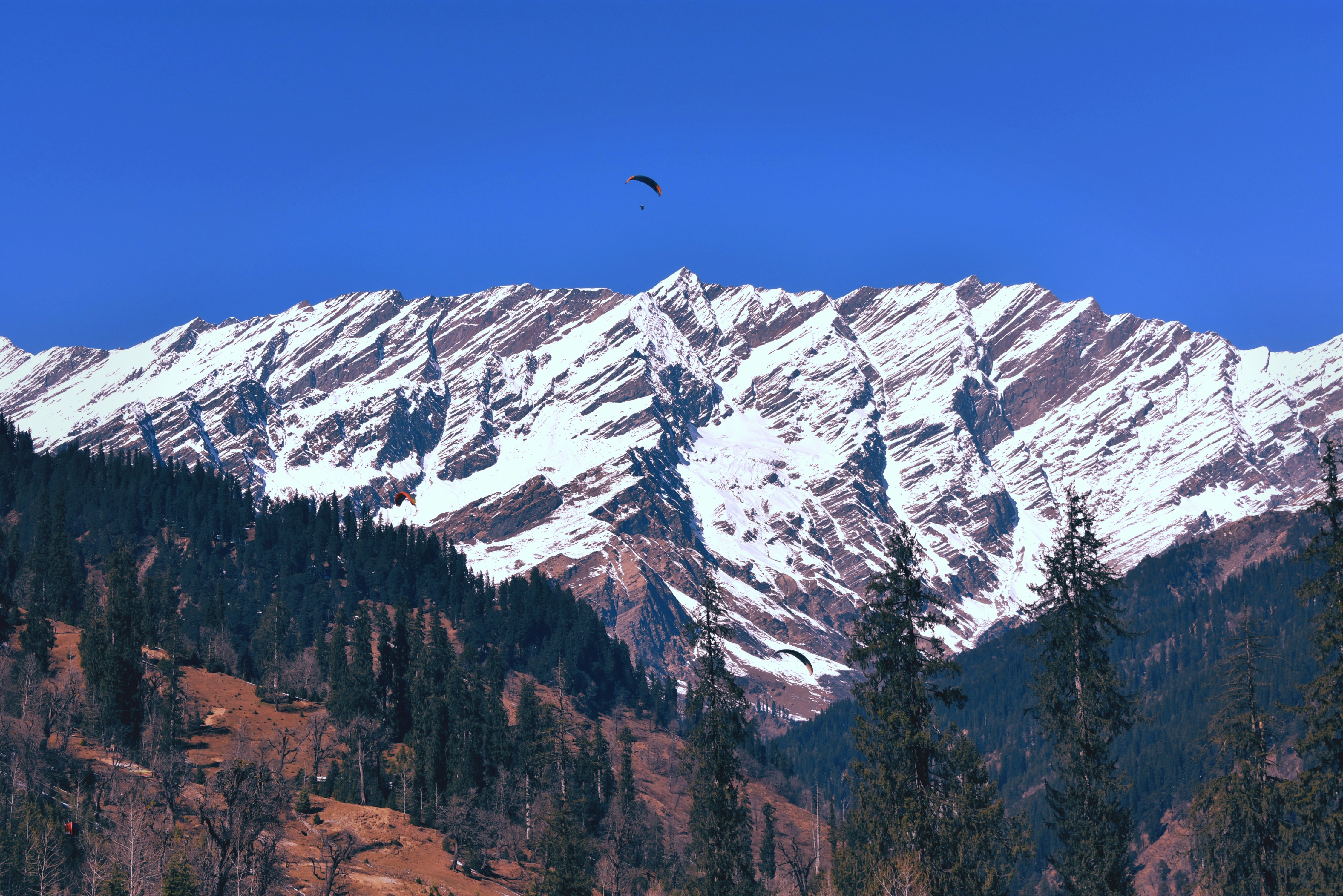 Paraglider Tracing a Narrow Arc Above Snow-Dusted Alpine Crest