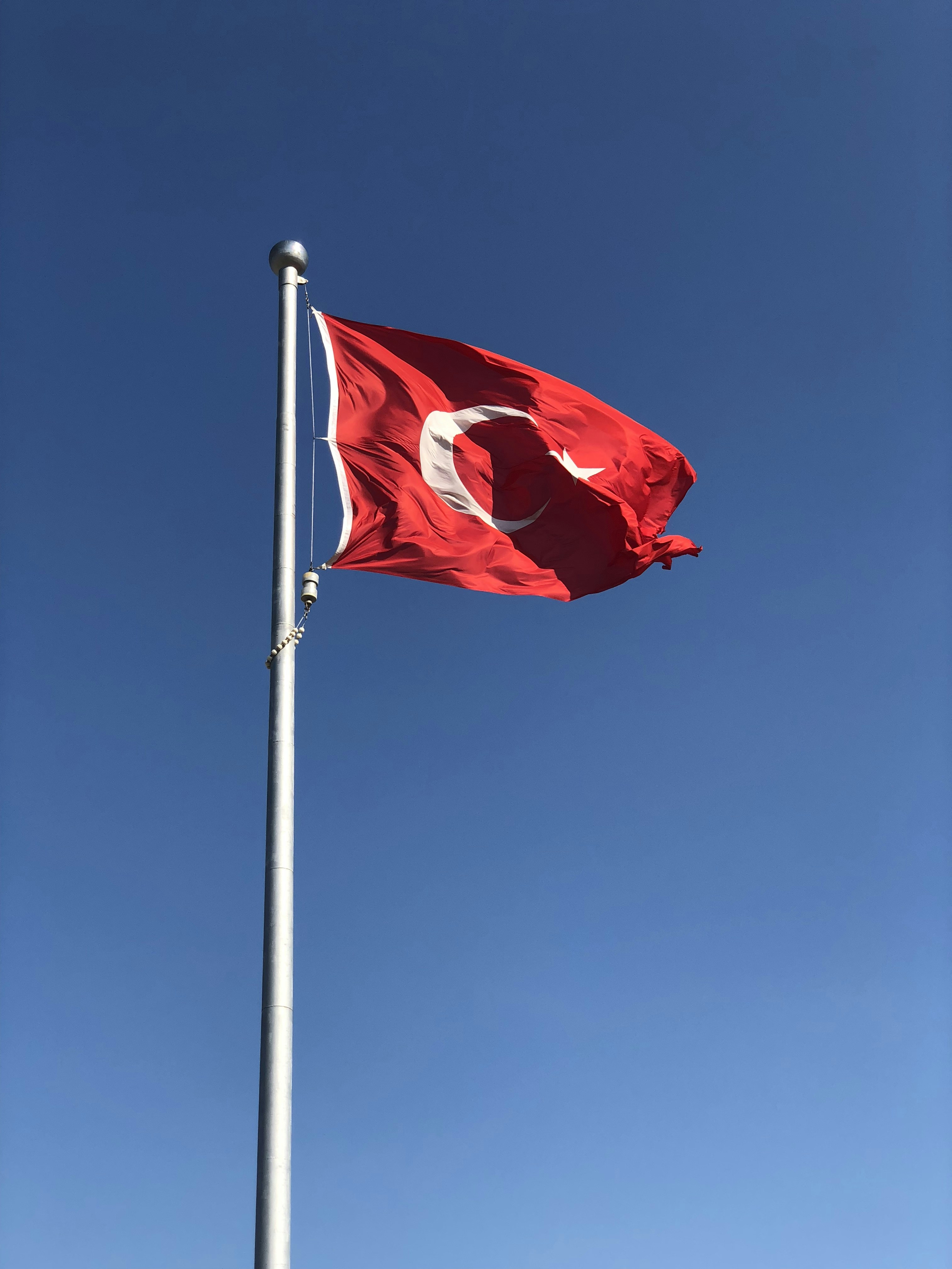 Turkish flag billowing against a clear blue sky, symbolizing national pride and identity.