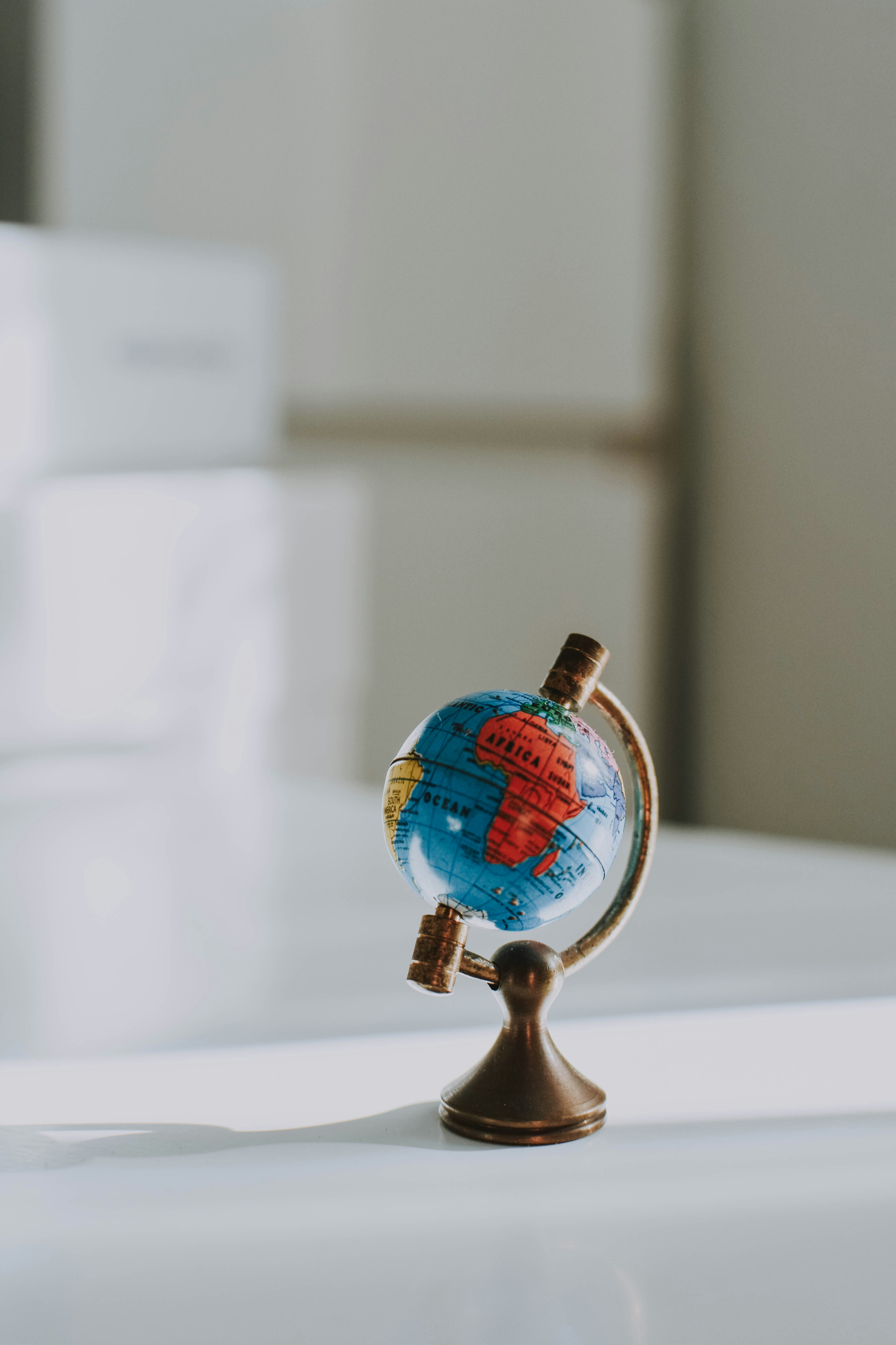 A small globe sitting on top of a white table photo – Free Globe Image ...