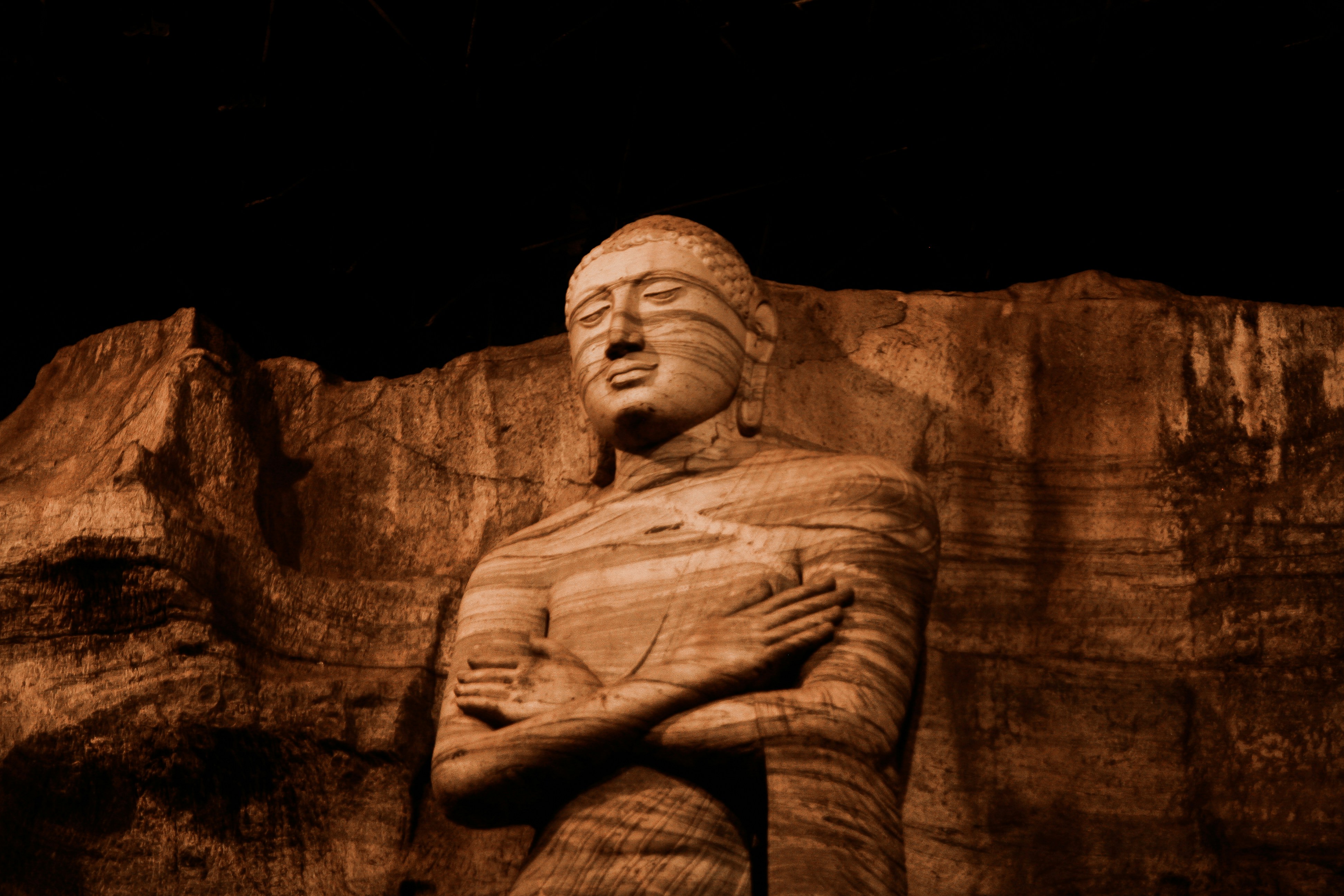 Amber Sentinel: Night-Bathed Buddha Stands Against a Cliff