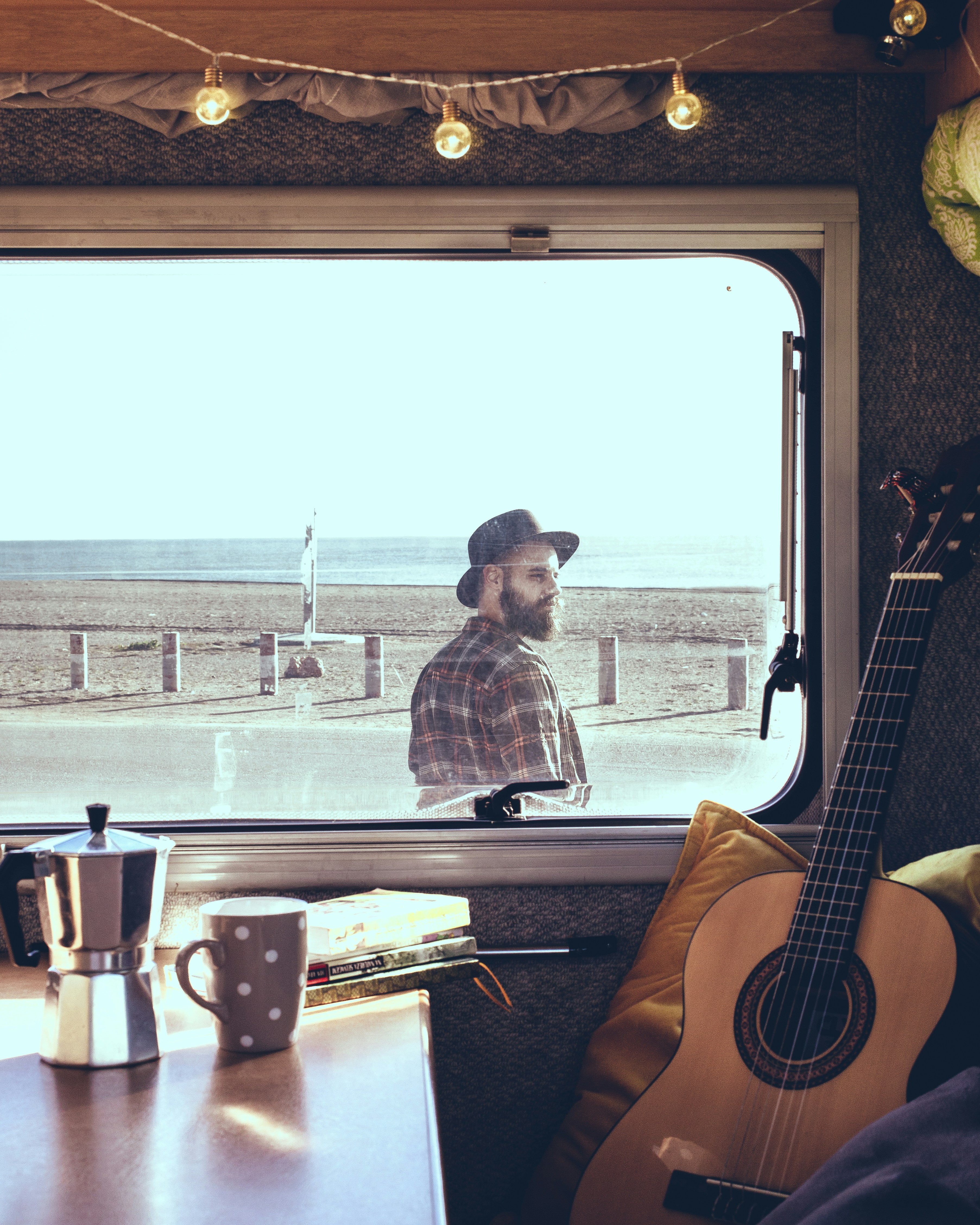 Horizon Gaze from a Camper: Bearded man in a hat framed by the seaside window