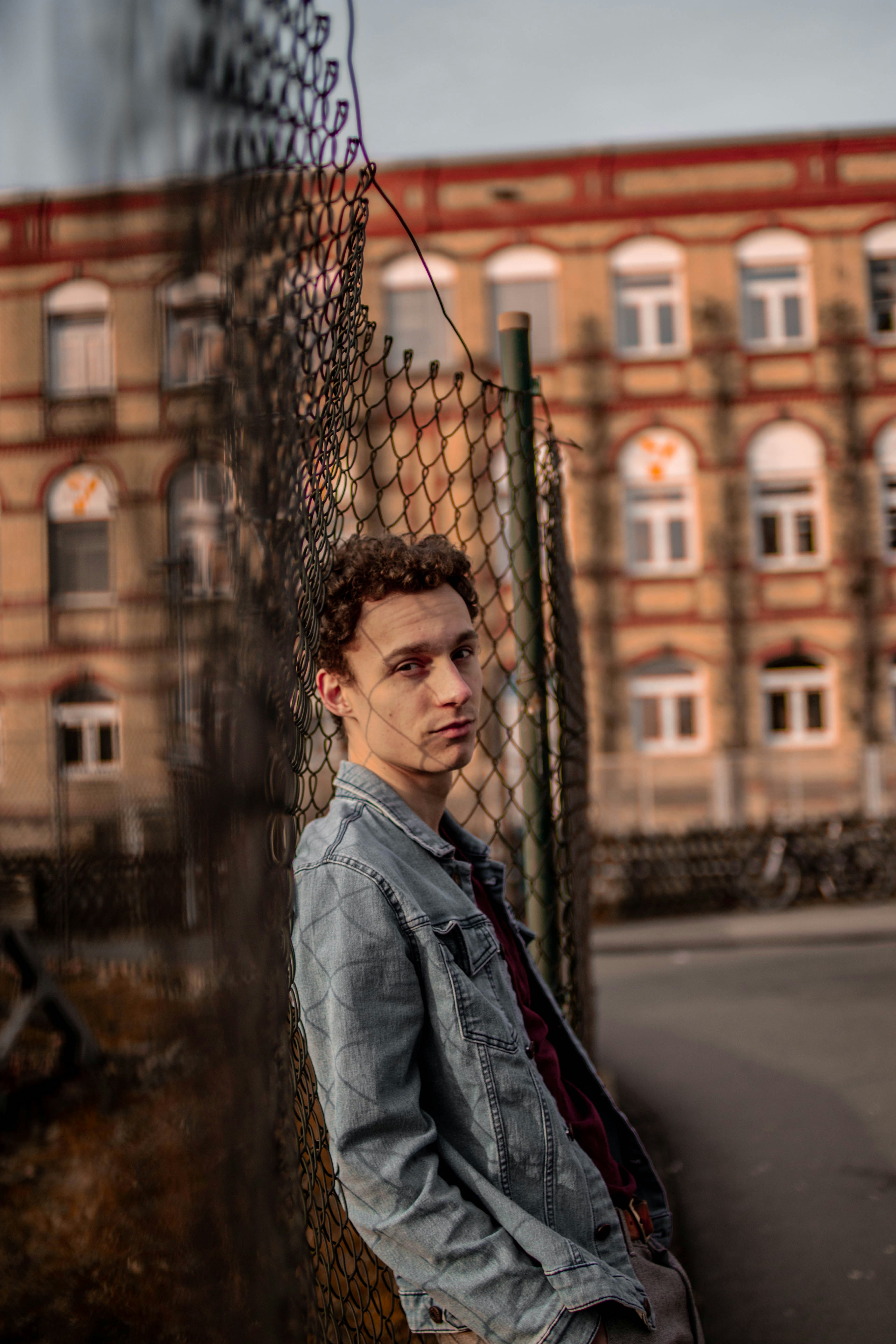 Man wearing blue jacket standing beside cyclone fence photo – Free Man ...