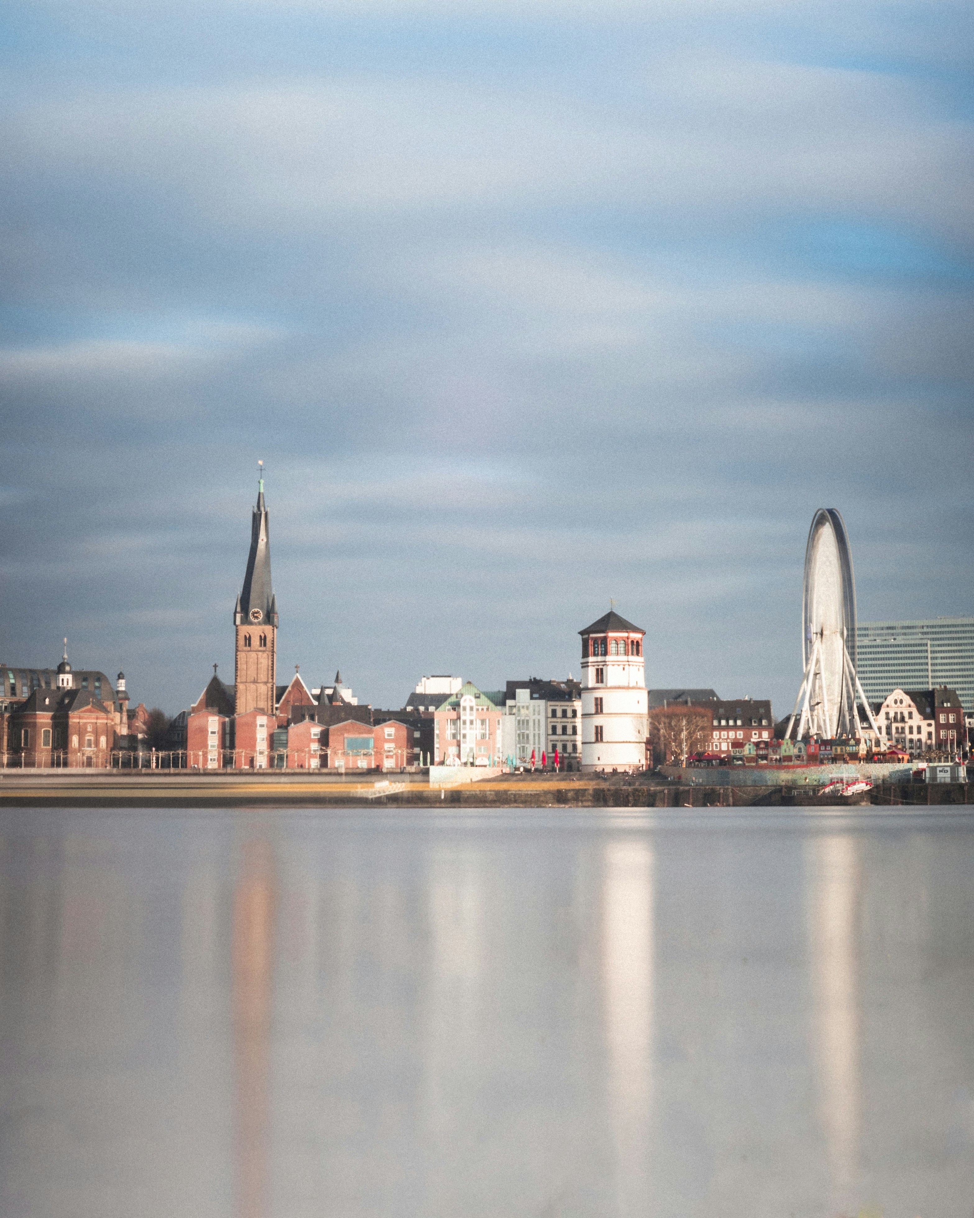 Spire and Ferris Wheel: Riverside Cityscape at Dusk