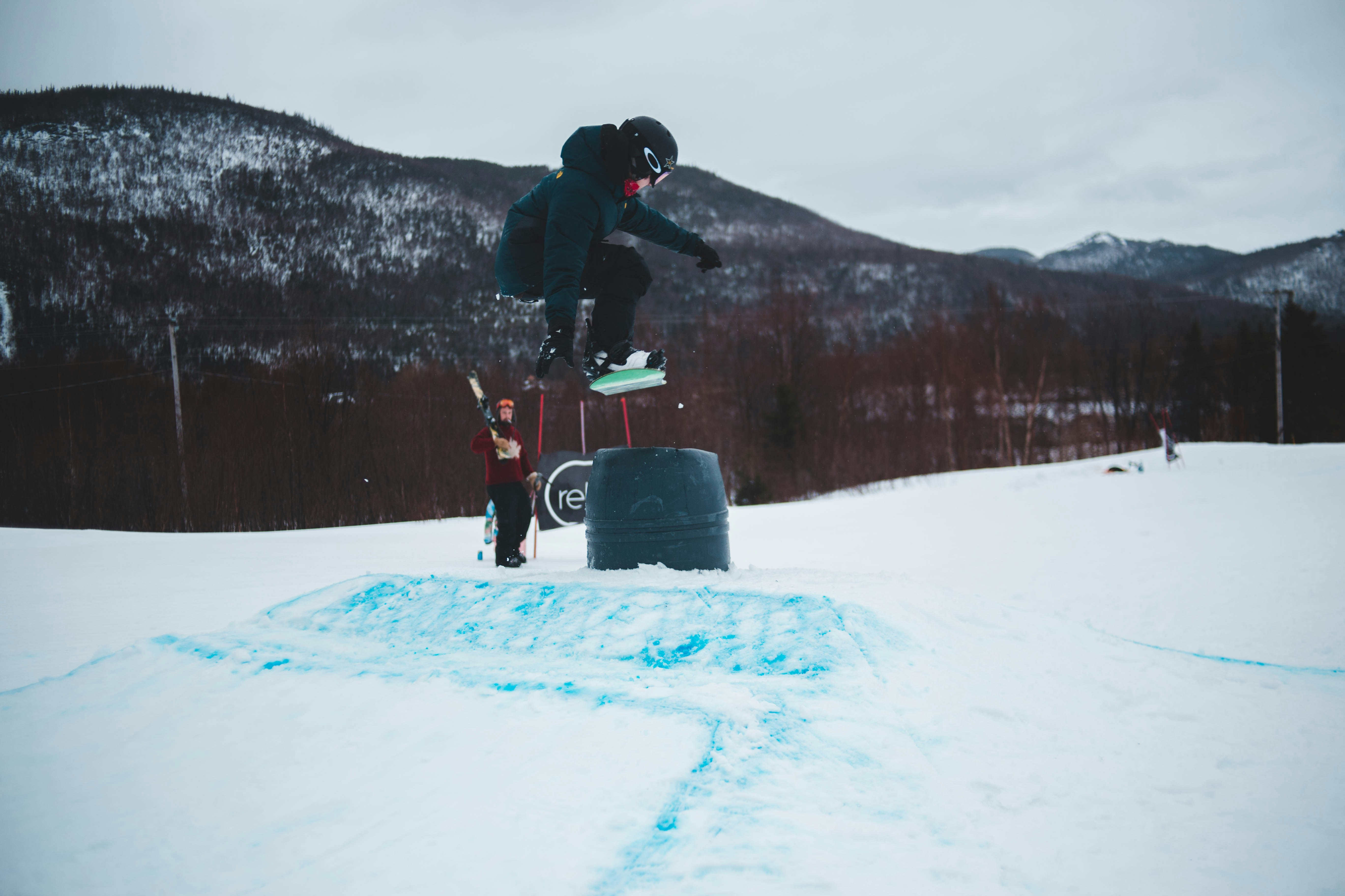 Midair Trick Over a Snow Ramp Against a Mountain Backdrop