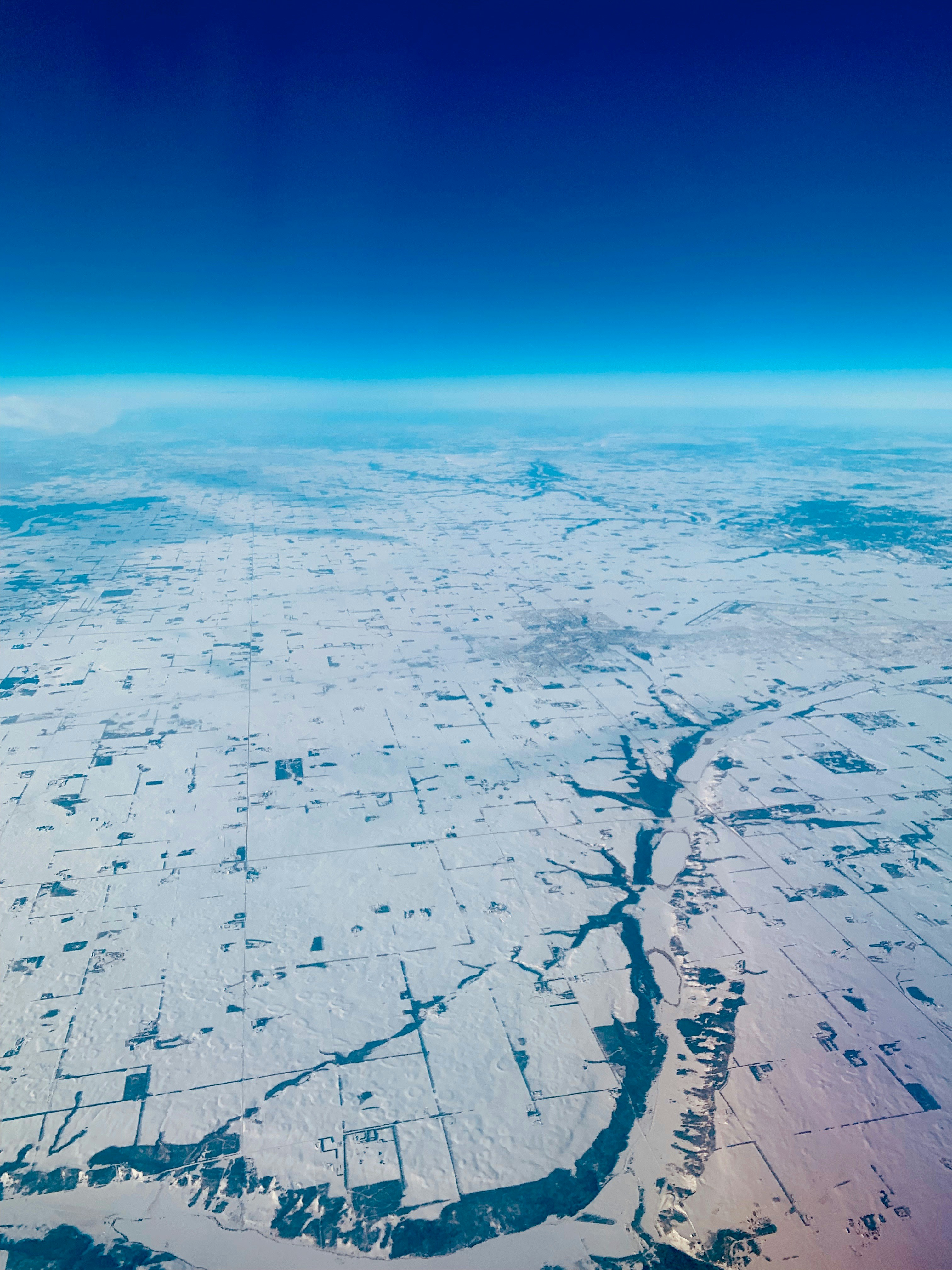 Riven Ice Grid: Aerial Snapshot of a Snowfield Carved by a Winding River