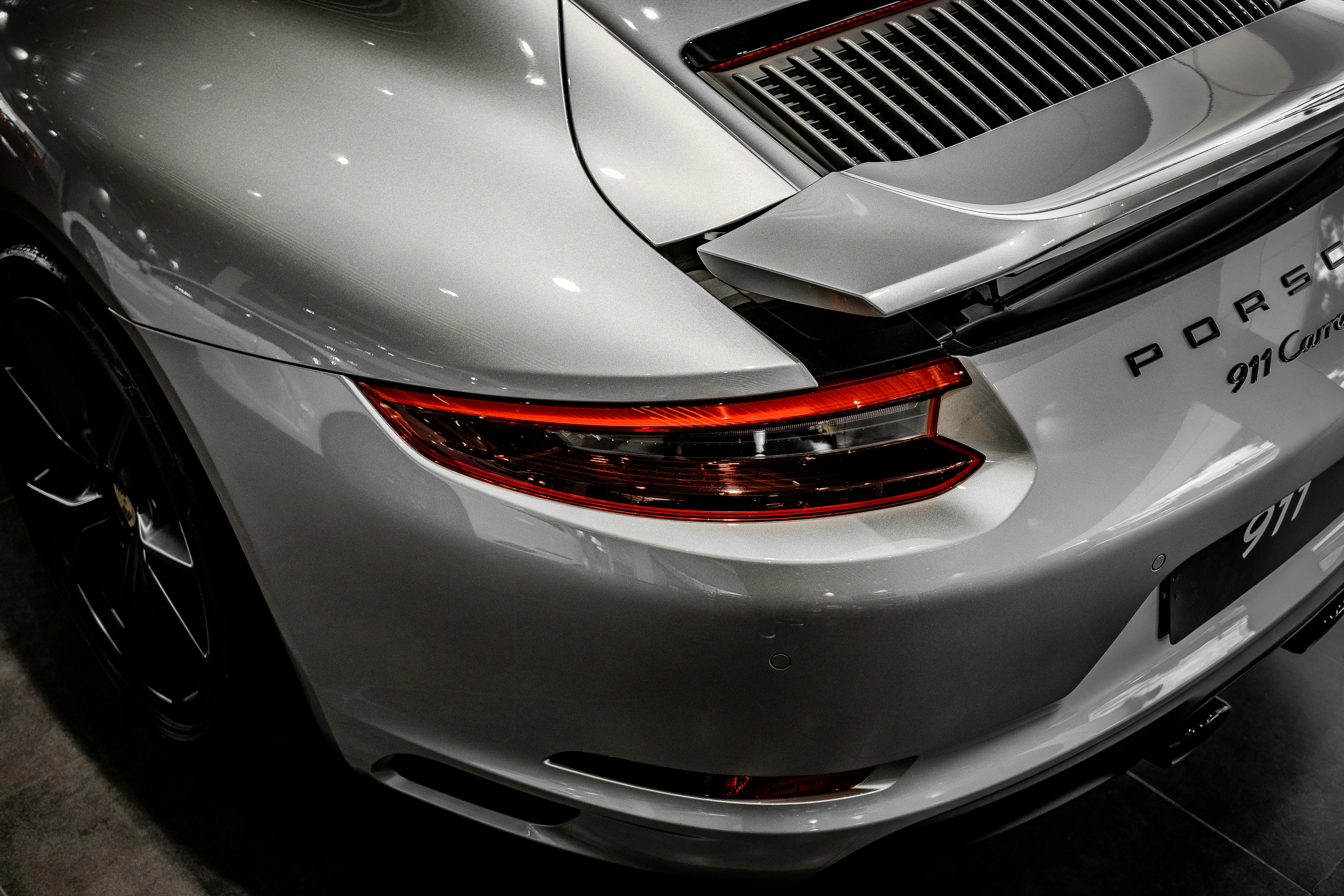 Close-up of a silver sports car's rear, highlighting the curved taillight and aerodynamic design.