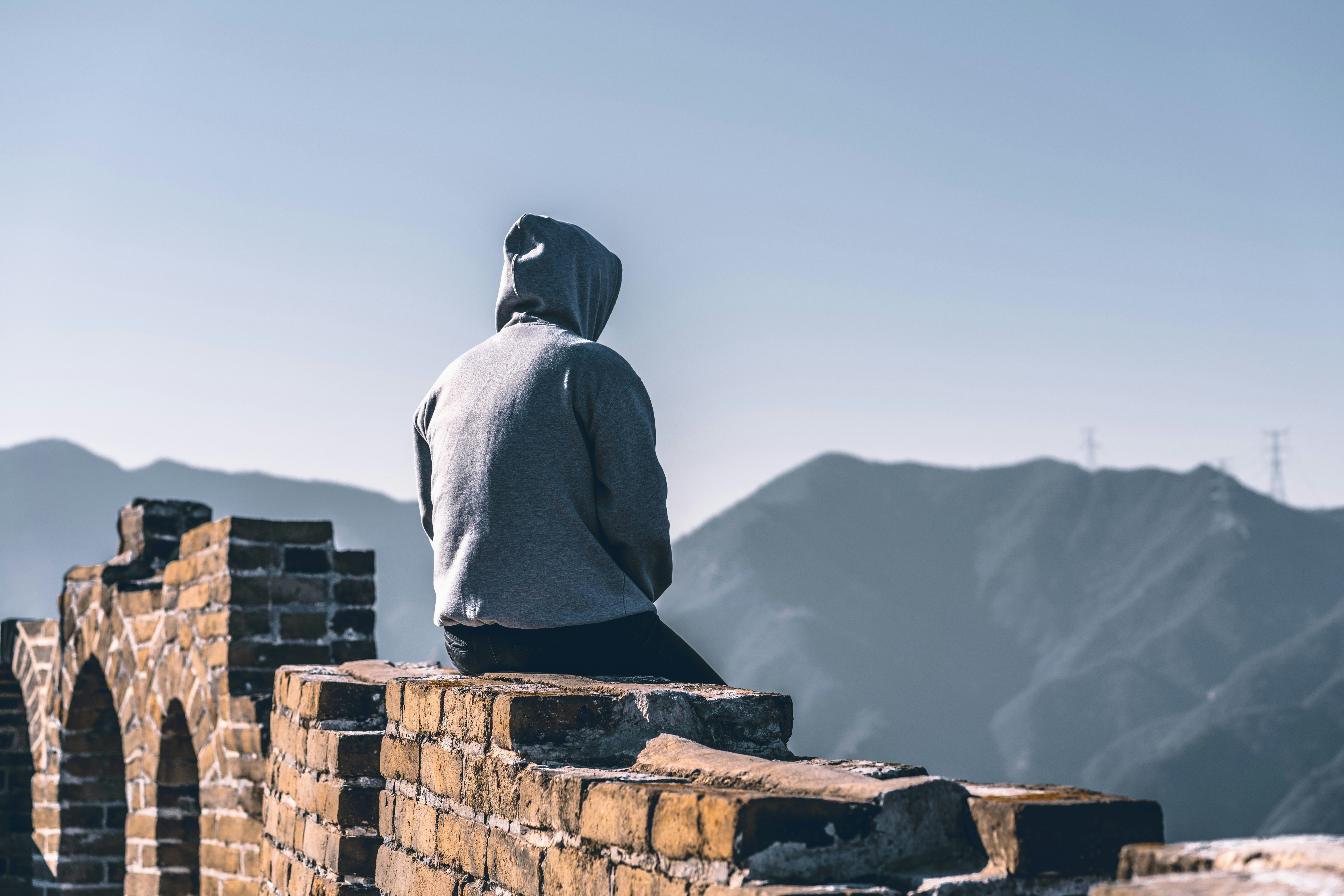 Foto Persona con capucha gris sentada en una pared de ladrillo – Imagen ...