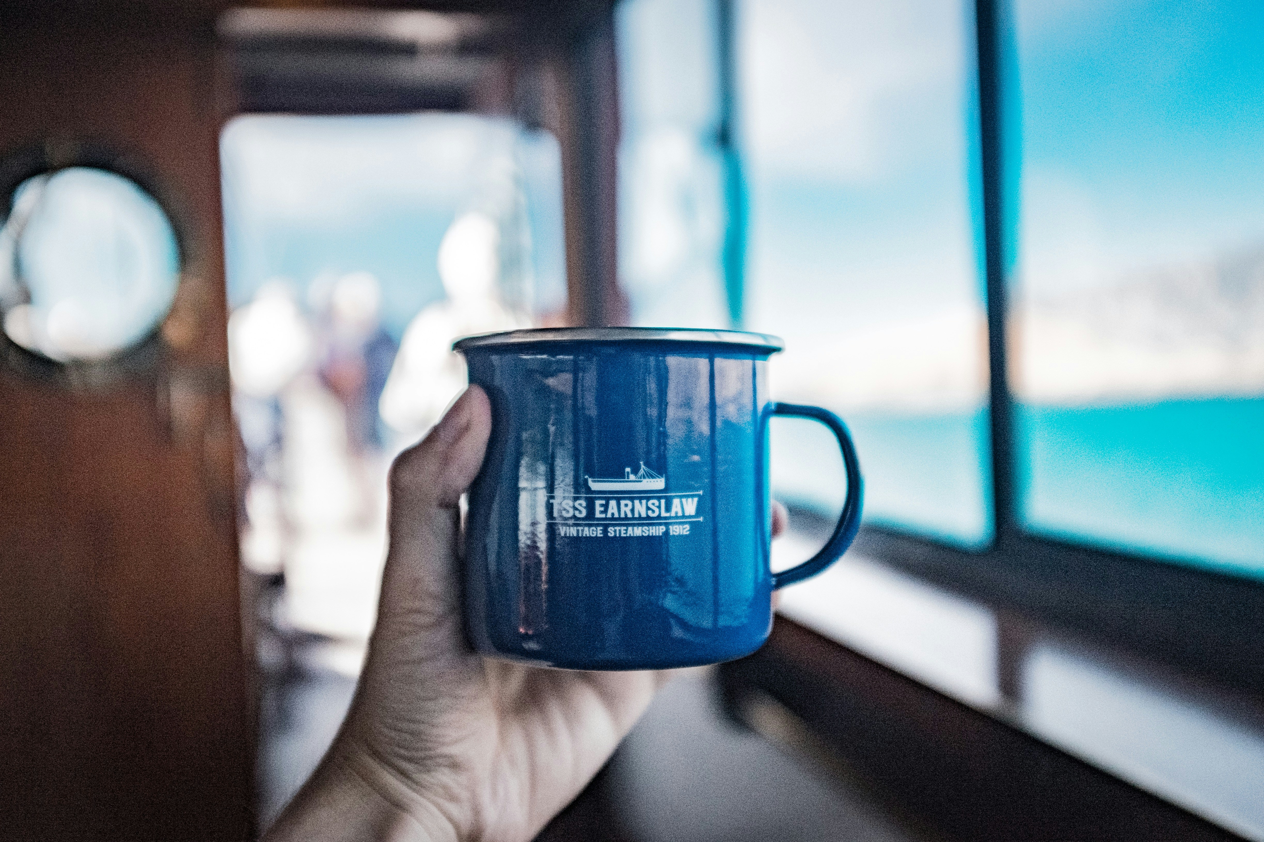 Blue Mug in Focus: A Handheld Moment Aboard a Vessel