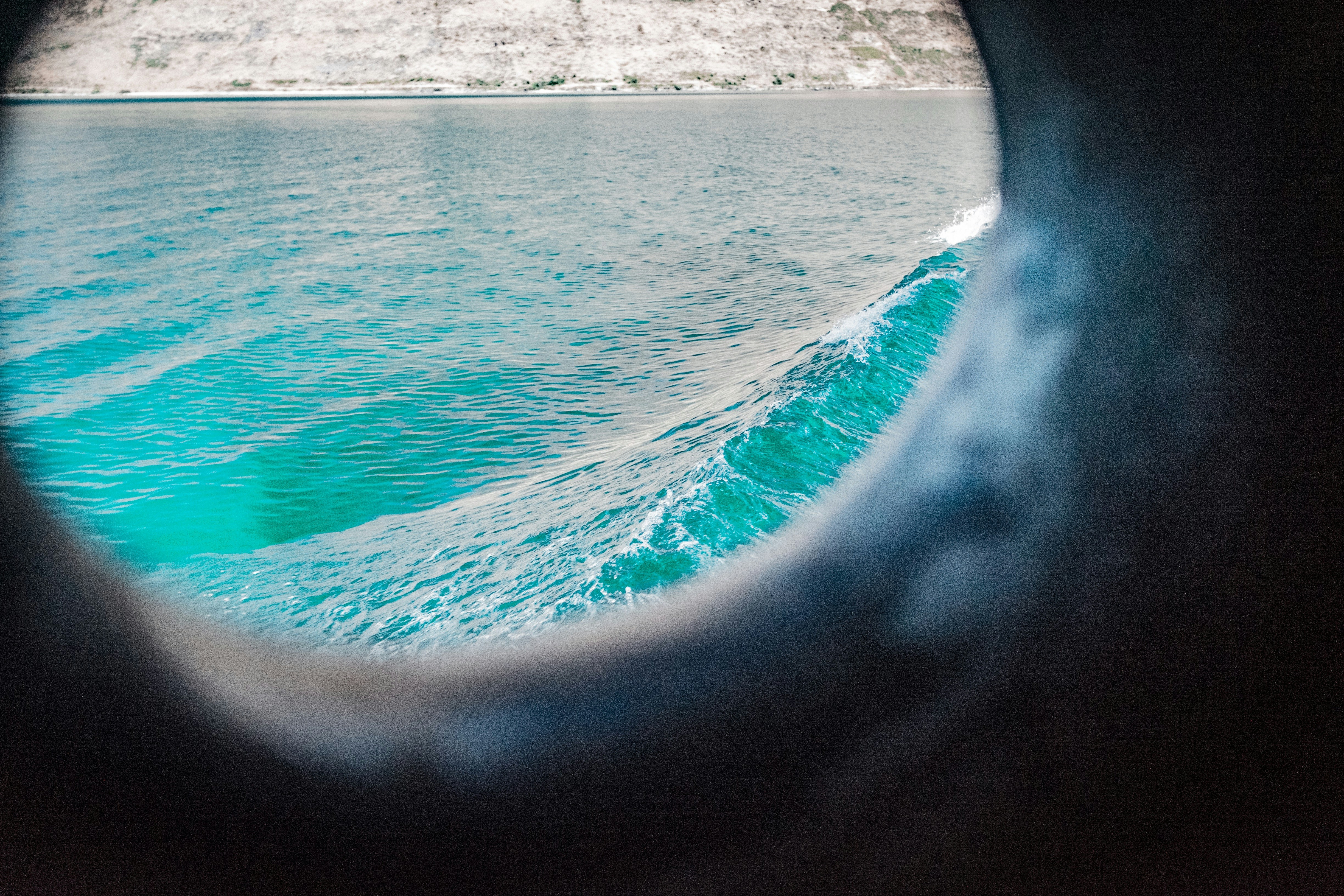 Circular Port Window Framing Turquoise Surf