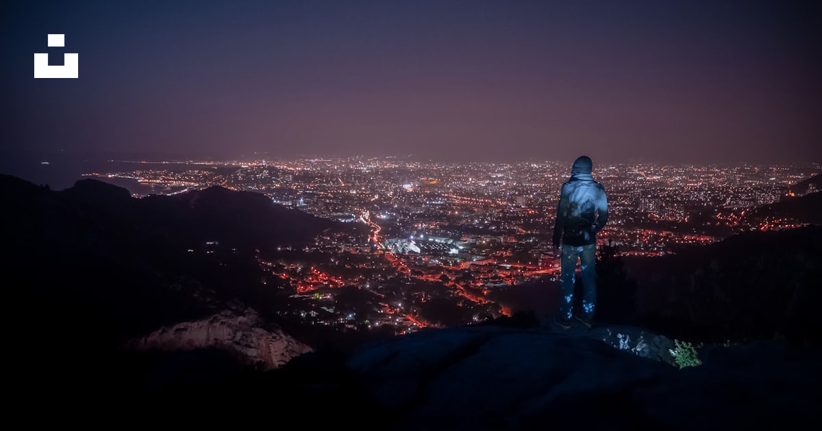 Silueta De La Persona De Pie Cerca De Los Edificios Iluminados Durante