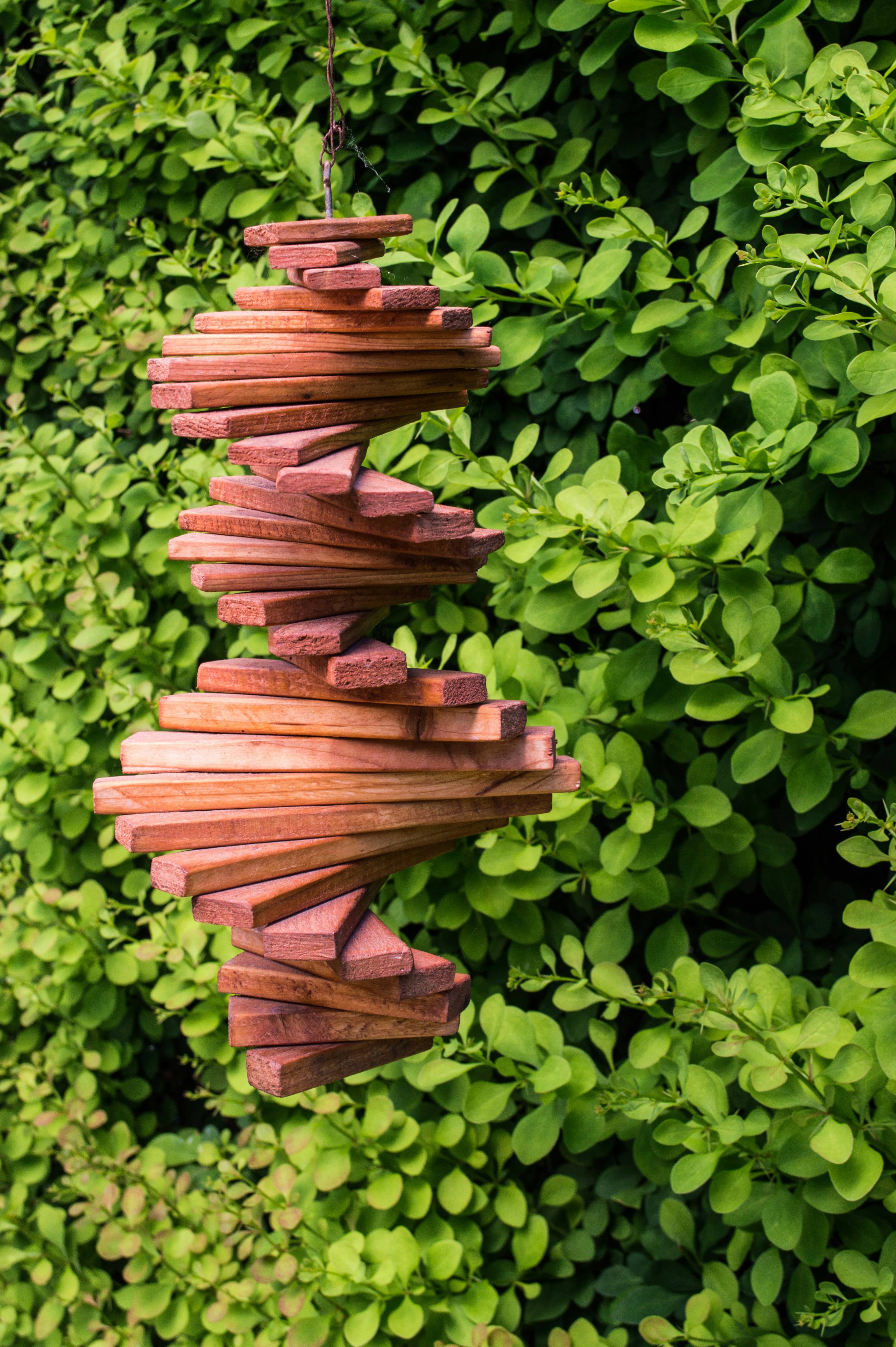 Spiral-Stacked Wood Wind Chime Adrift Among Emerald Foliage