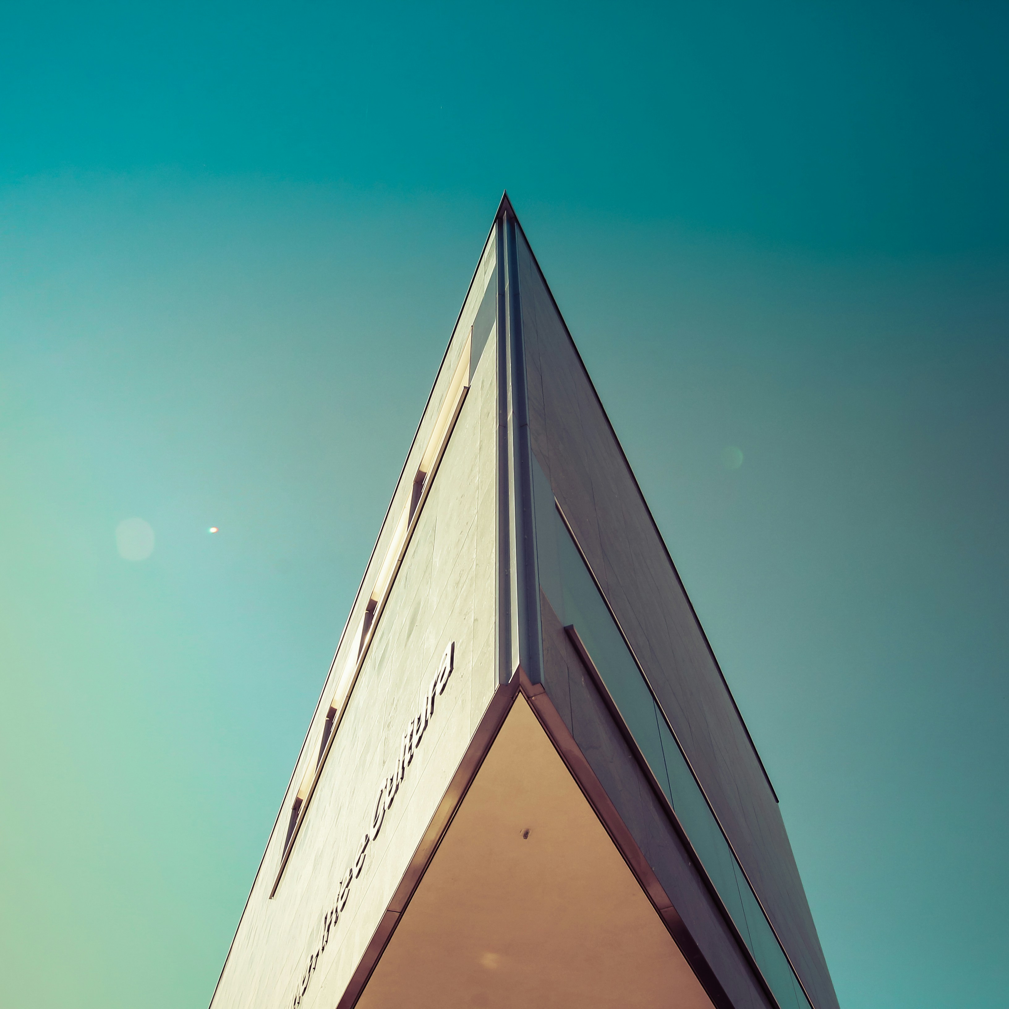 White pointed concrete building with sharp angles set against a clear turquoise sky.