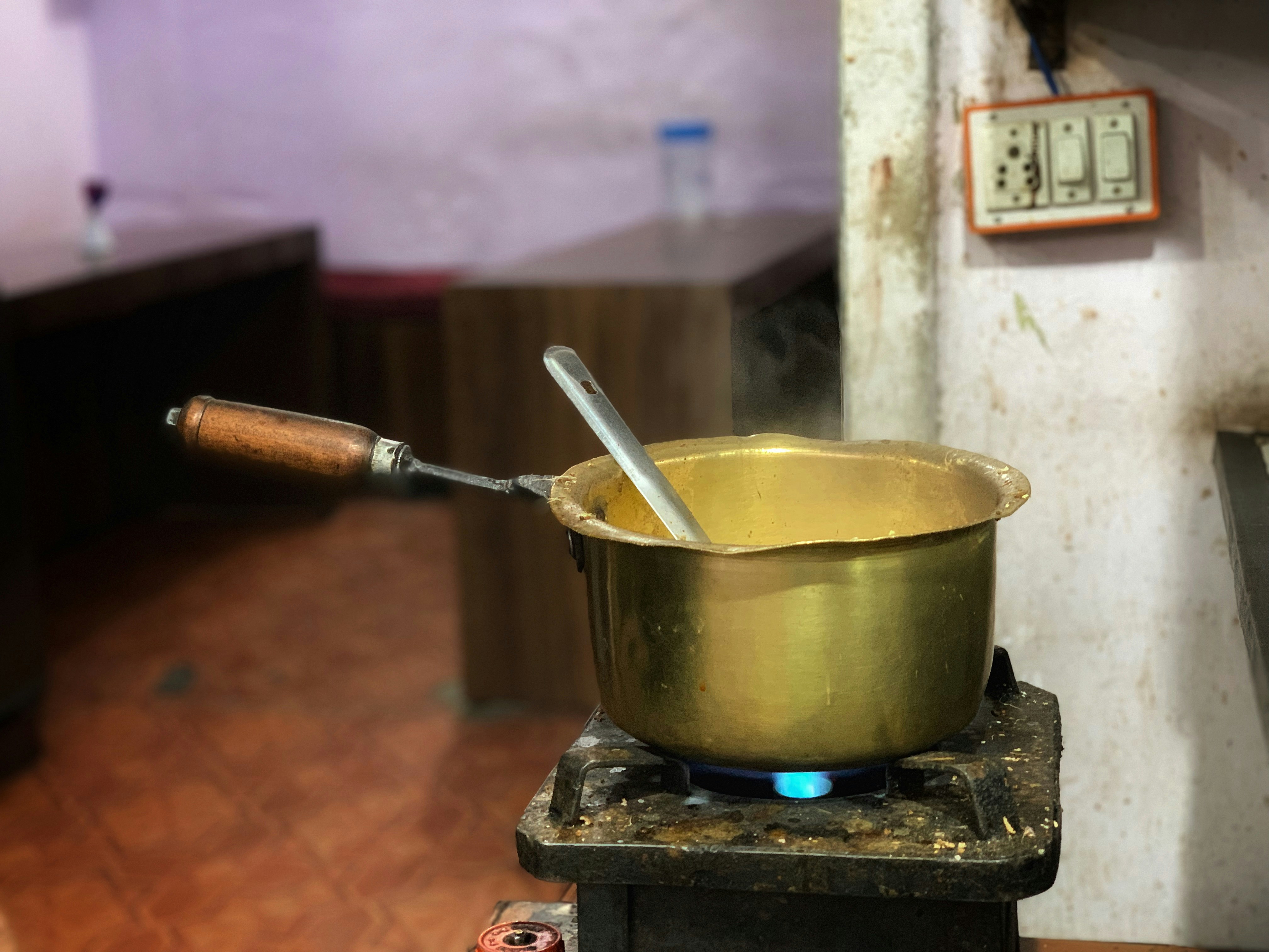 Brass pot steaming on a small stove in a cozy, dimly lit kitchen.