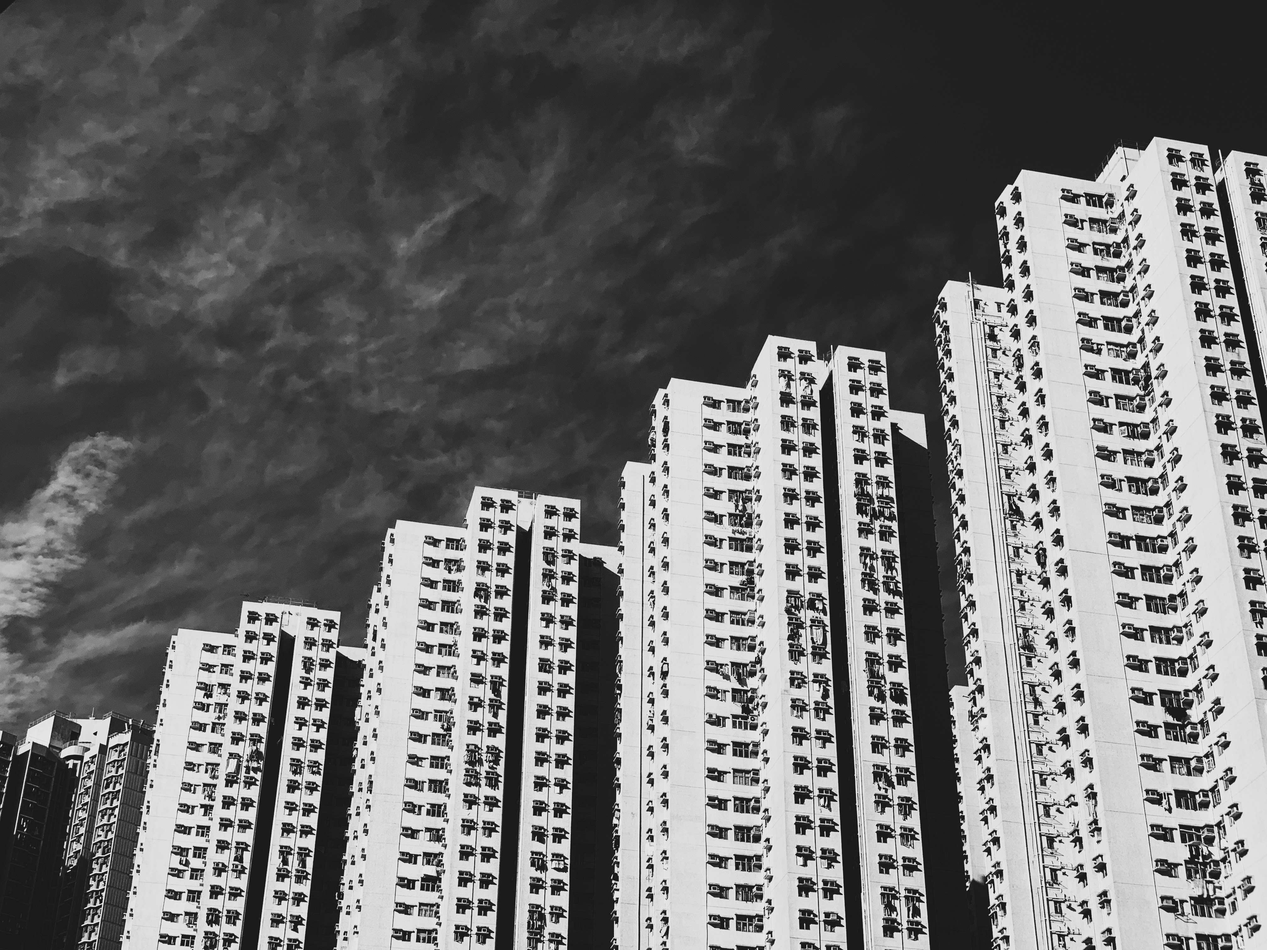 Black and white photograph of tall residential buildings under a textured sky.