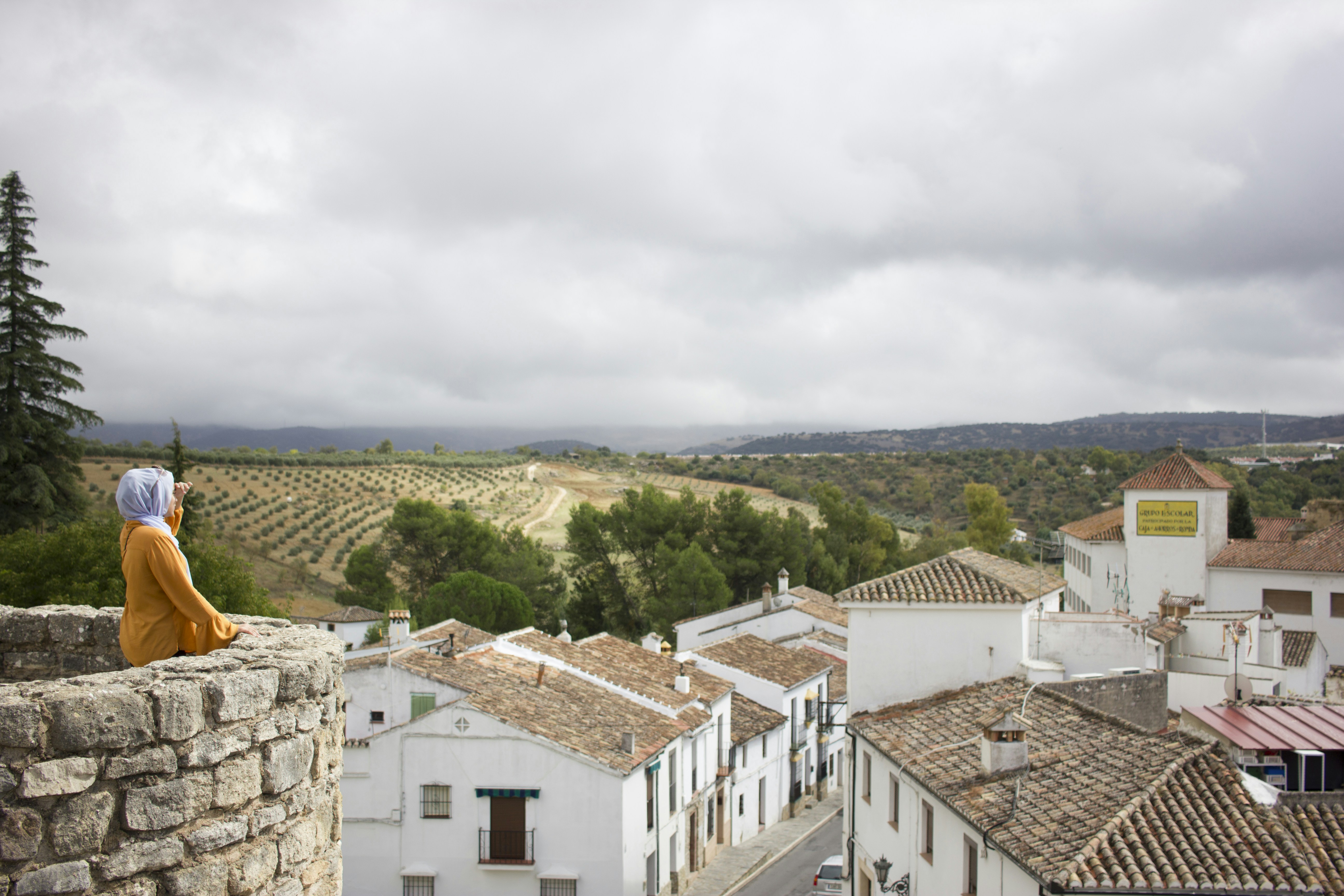 Lookout on the White-Washed Ridge: A Woman in Mustard Gazes Over a Village of Terracotta Tiles