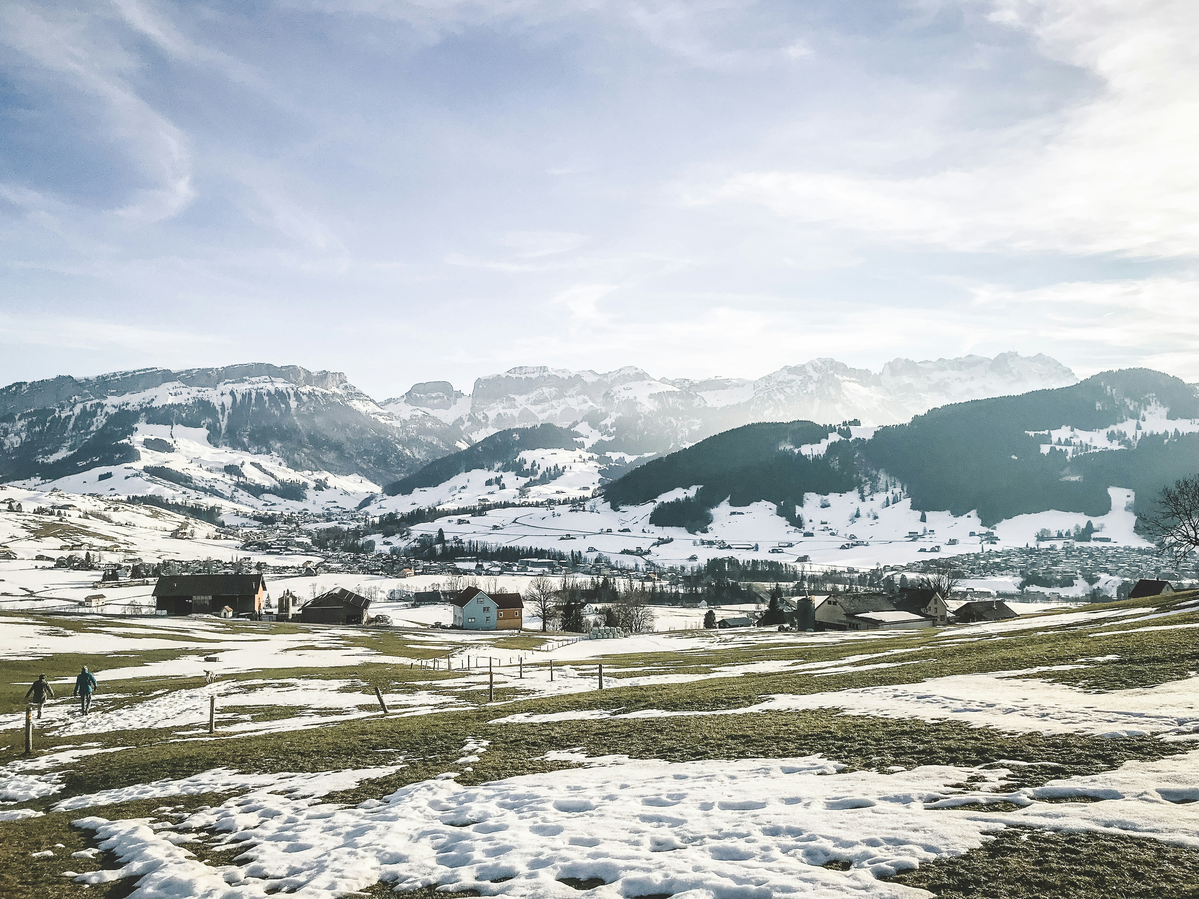 Snow-covered landscape with rolling hills and distant mountains, capturing the serene beauty of winter in the Alps.
