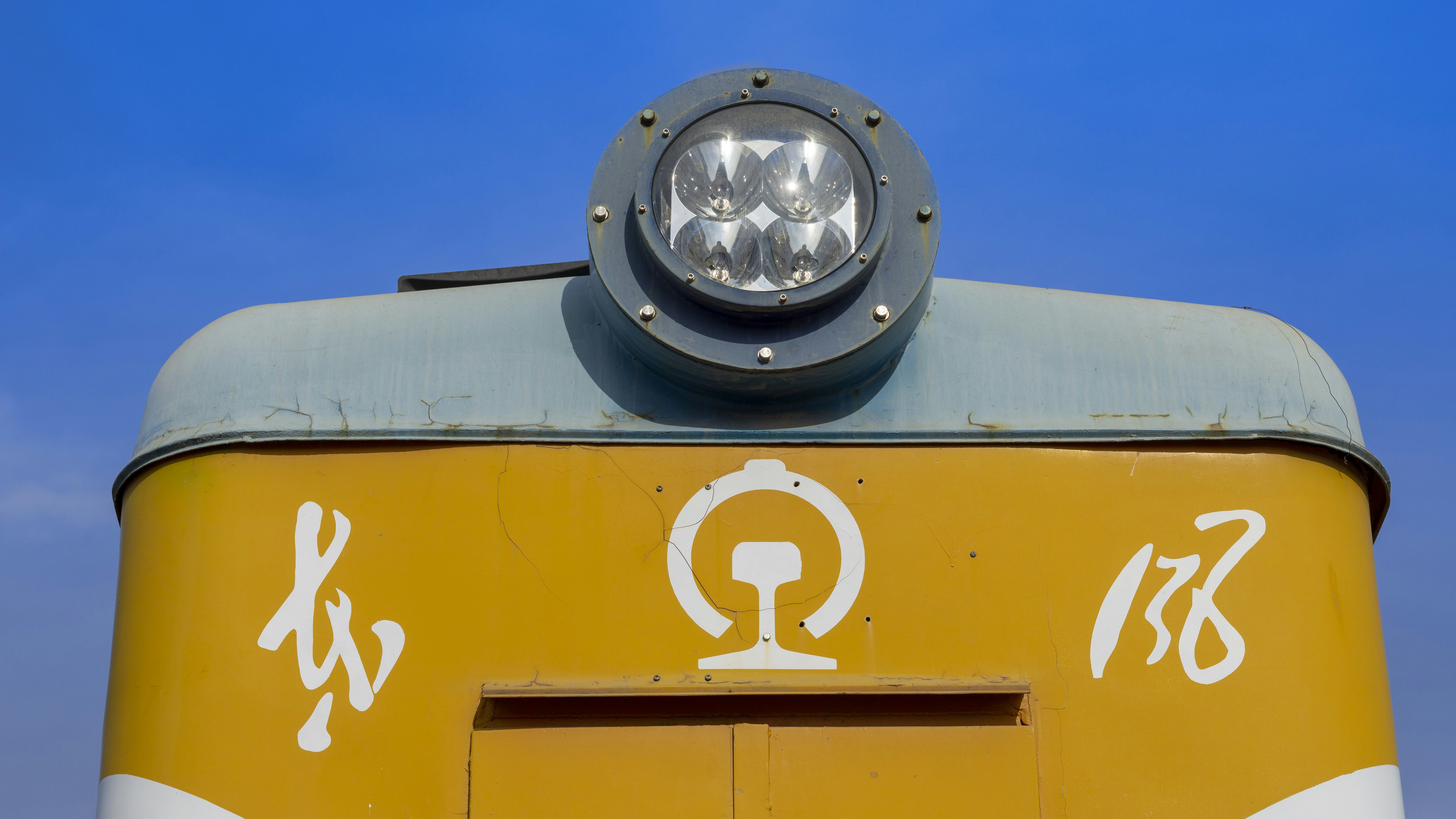 Round Headlamp Crown on a Weathered Yellow Locomotive Under a Bright Sky